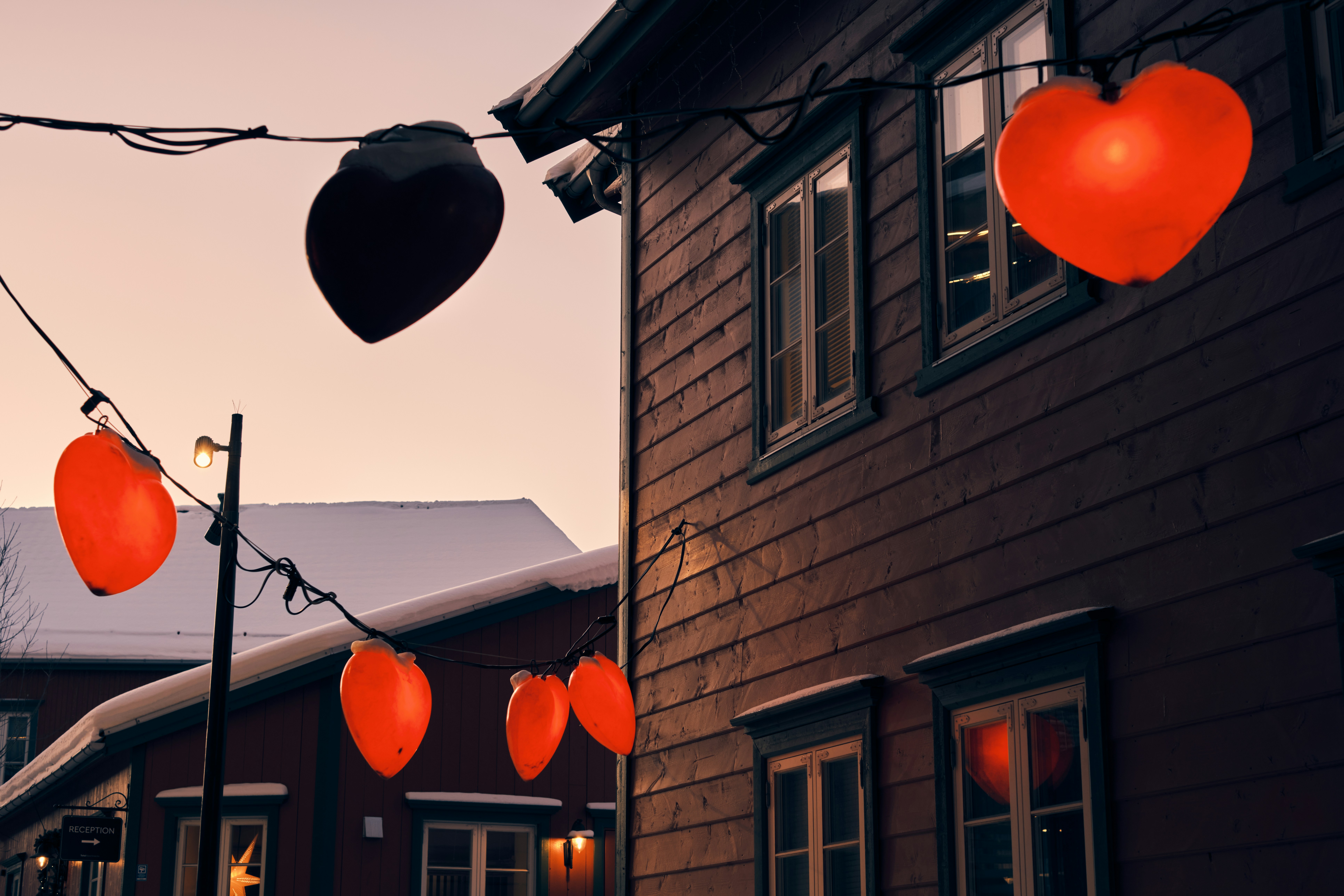 Floating hearts over a quiet neighborhood: dusk glow and warm lanterns