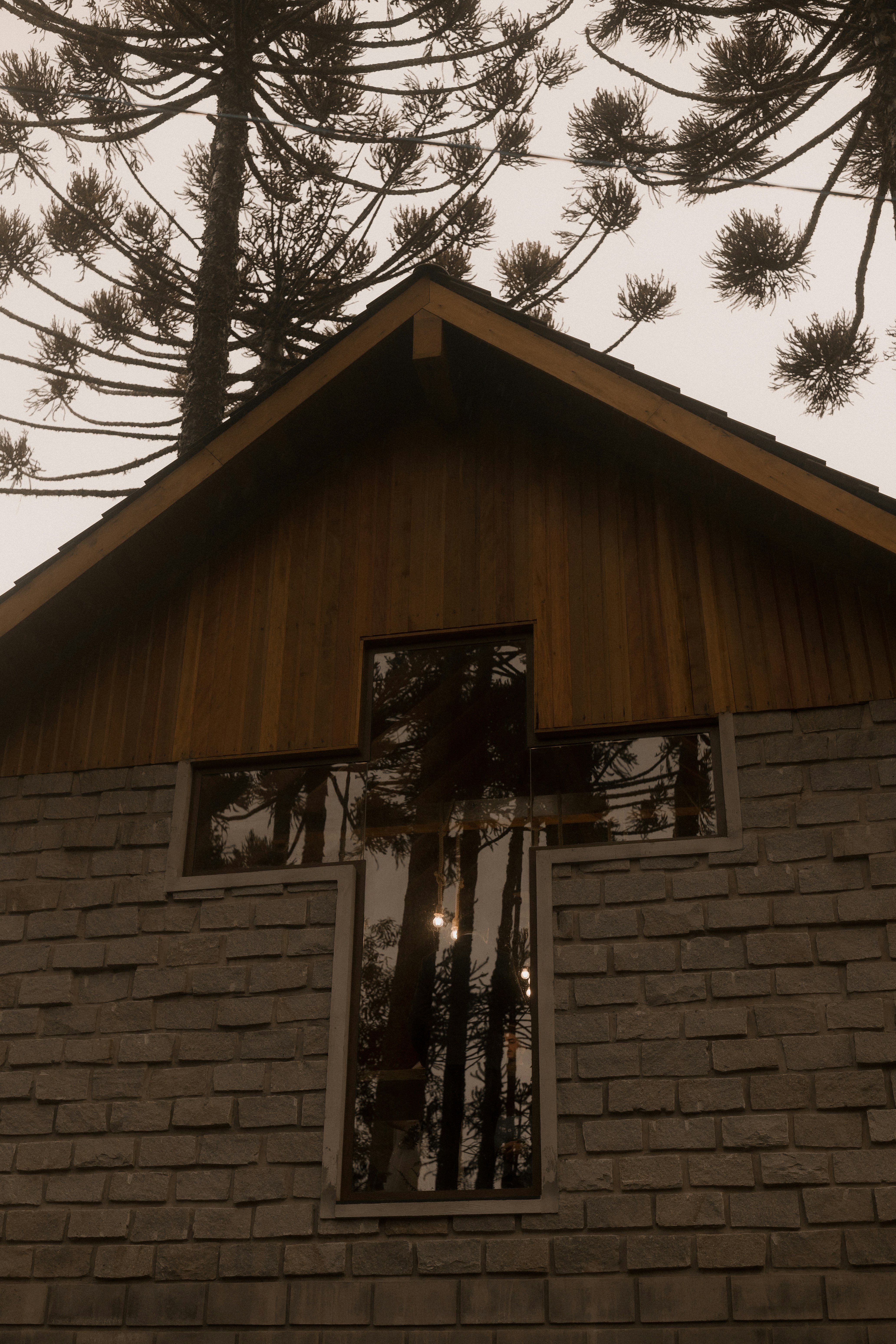 Cross-shaped Window Reflecting Pines Beneath a Wooden Gable