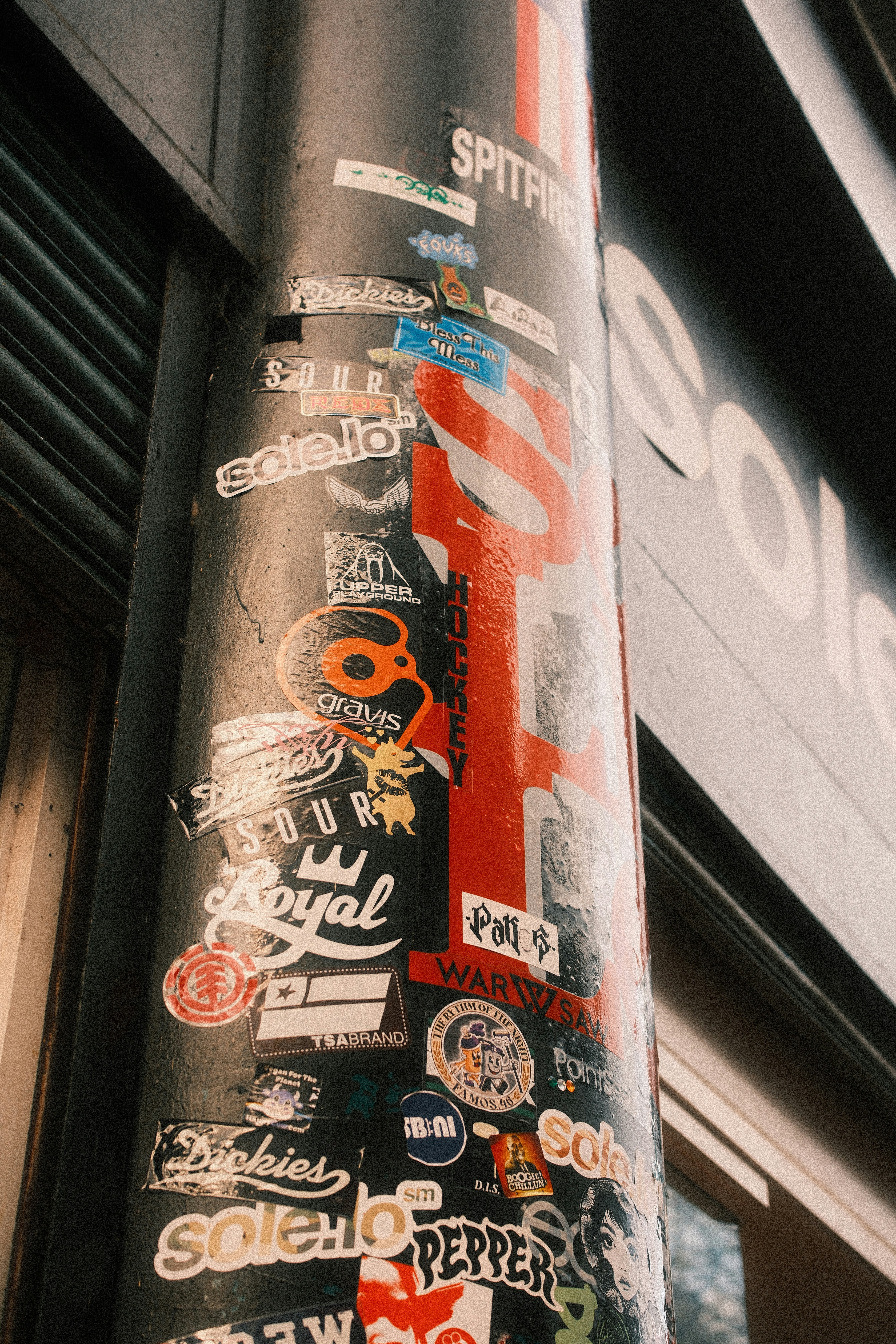 Stickered Pole: A Collage of Urban Emblems on a Street Sign Post