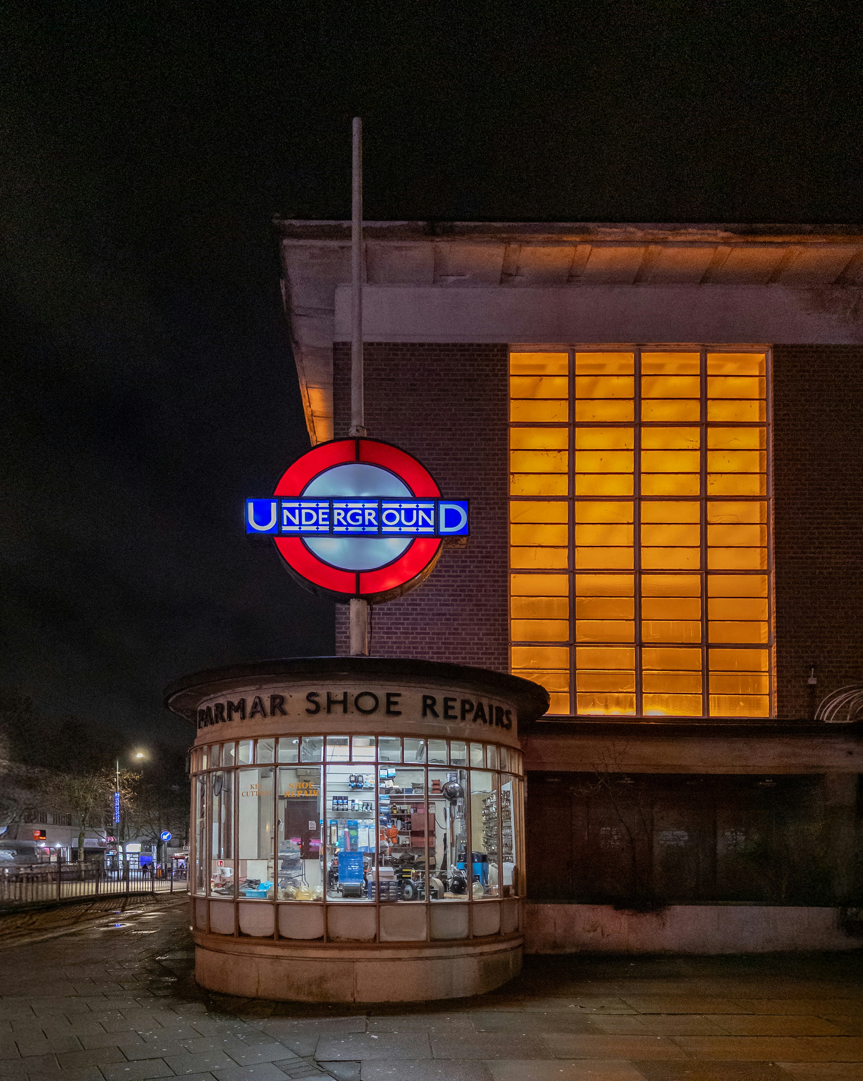 Night Circle: Underground Station Sign Above a Vintage Shopfront