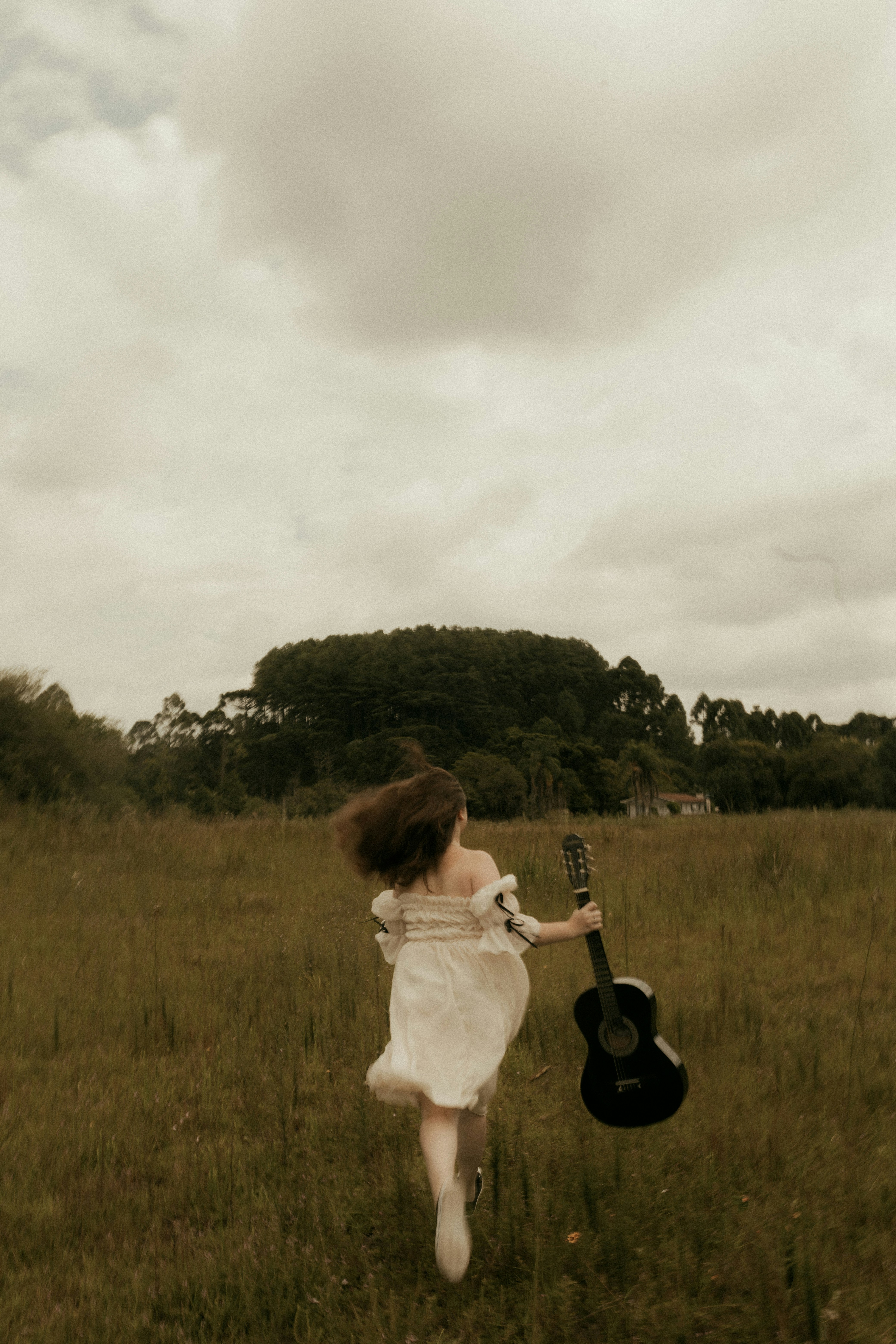 Runaway Melody: A Girl in White with a Guitar in an Open Field