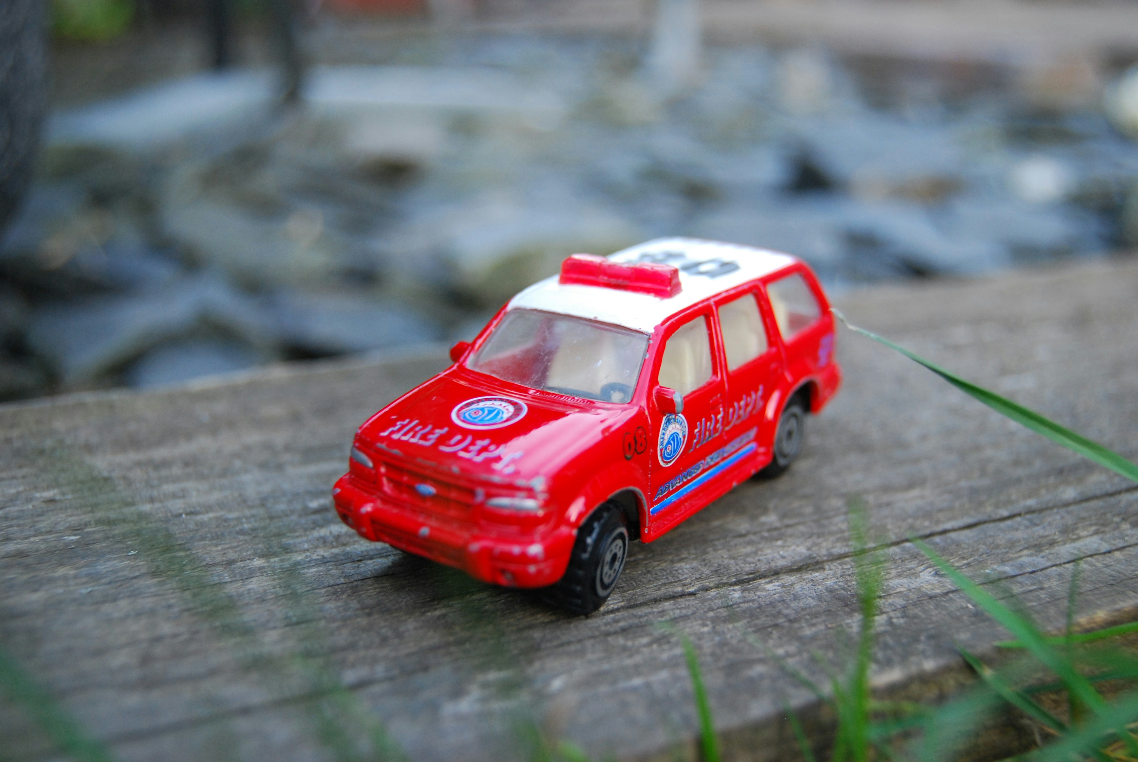 Mini Rescue: A Red Toy Car on a Weathered Log