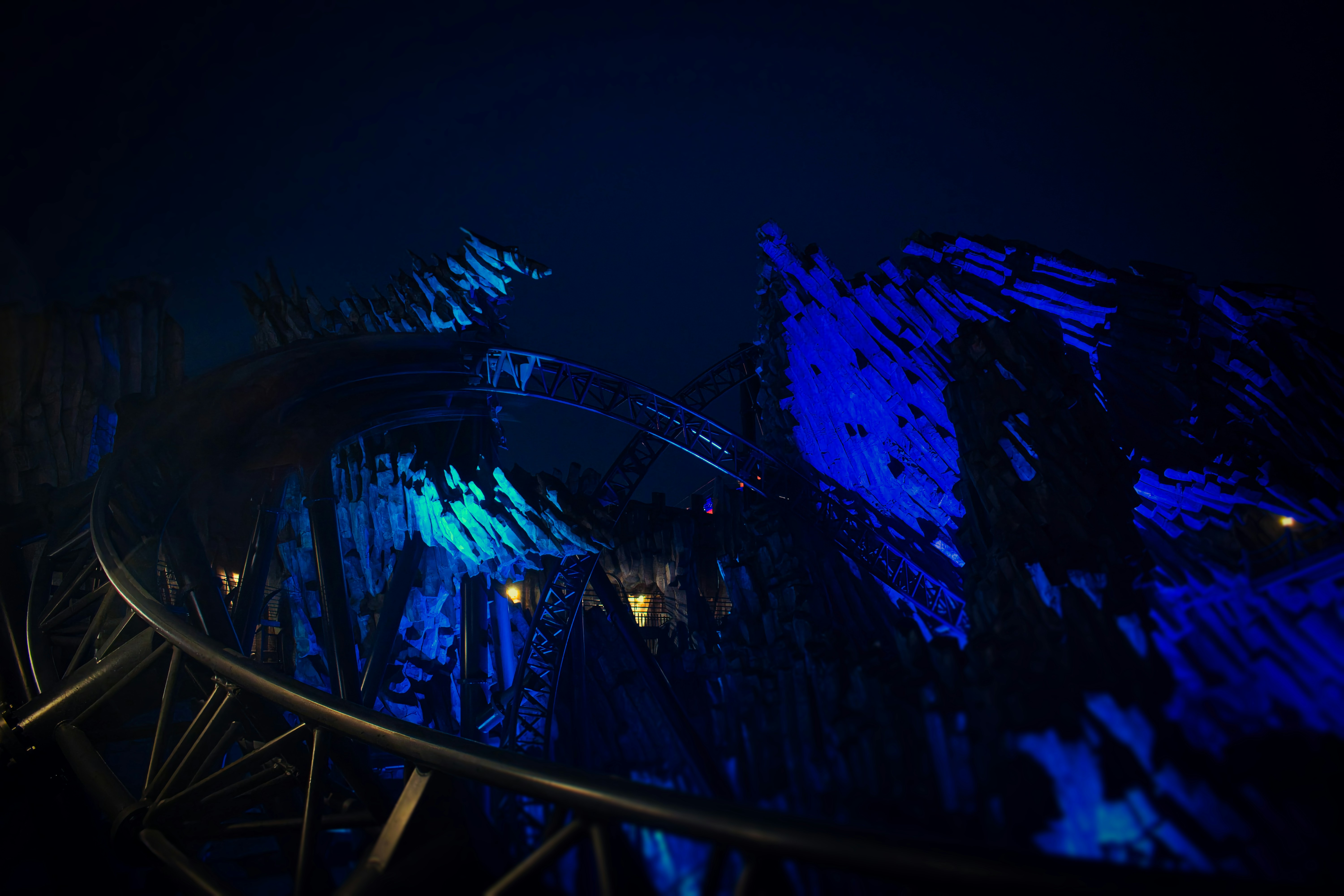 Midnight Coil: A Blue-Illuminated Roller Coaster Between Dark Peaks