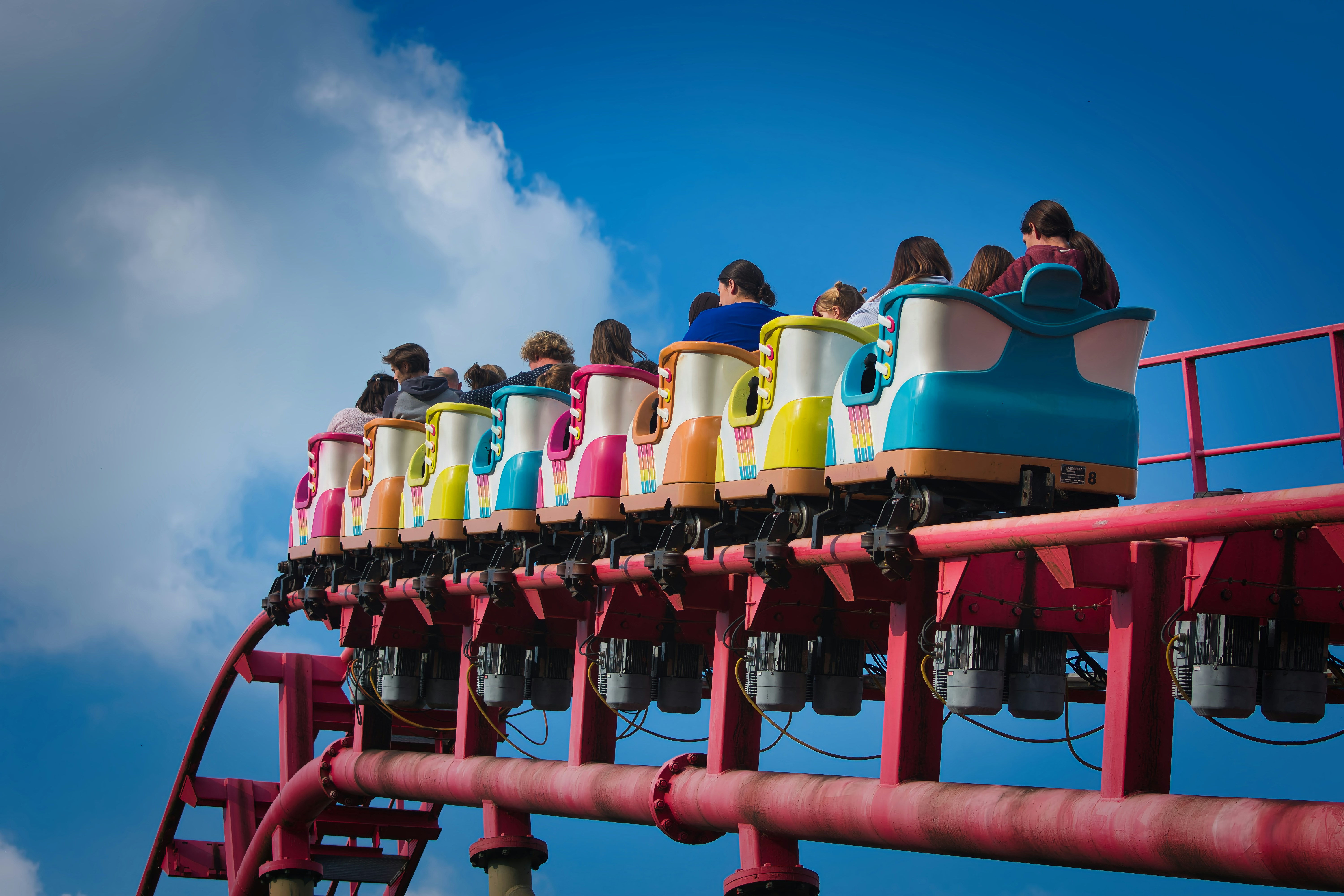 Colorful cars on a steel rollercoaster loop against a clear blue sky