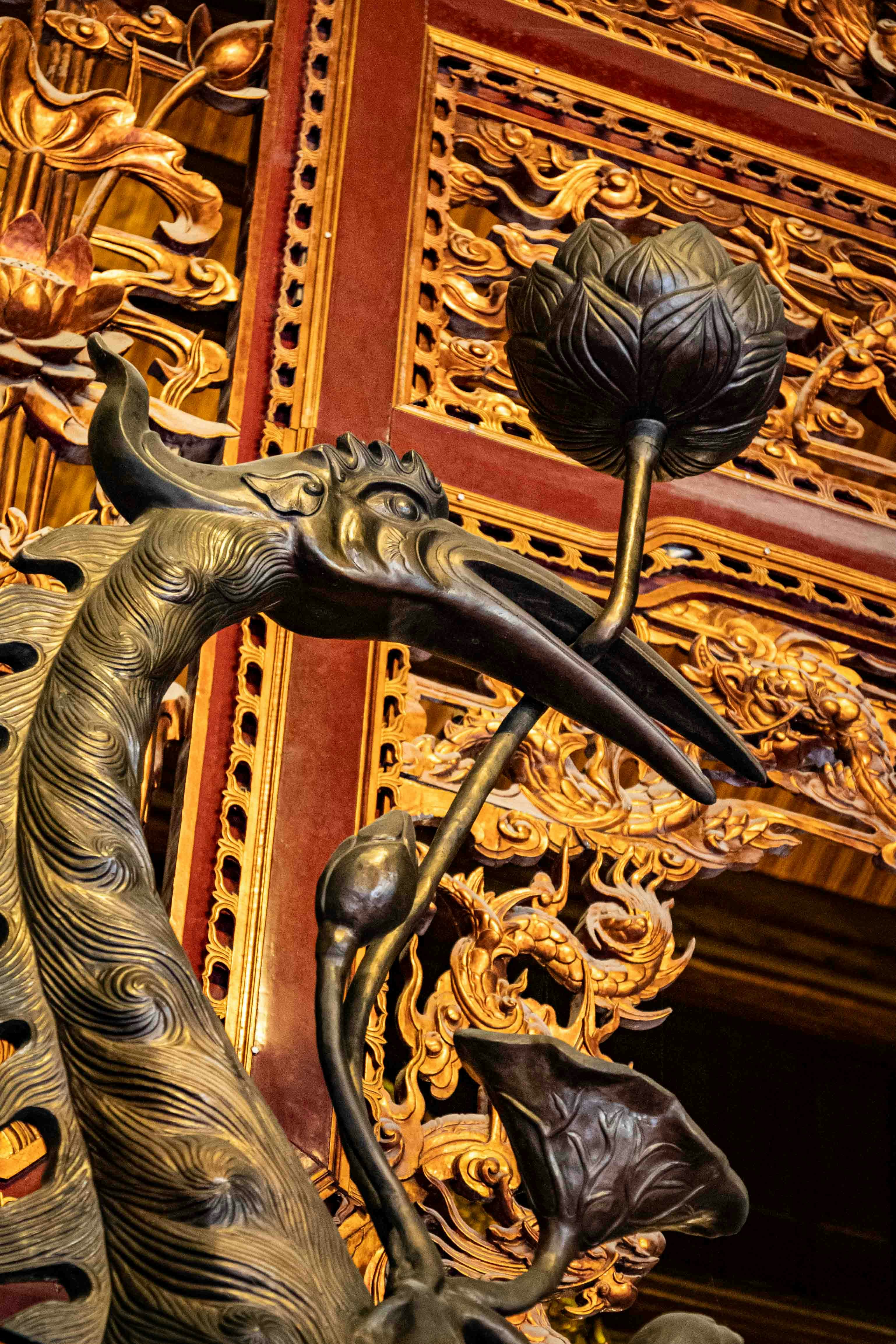 Intricate Bronze Crane Ornament Set Against Carved Golden Backdrop