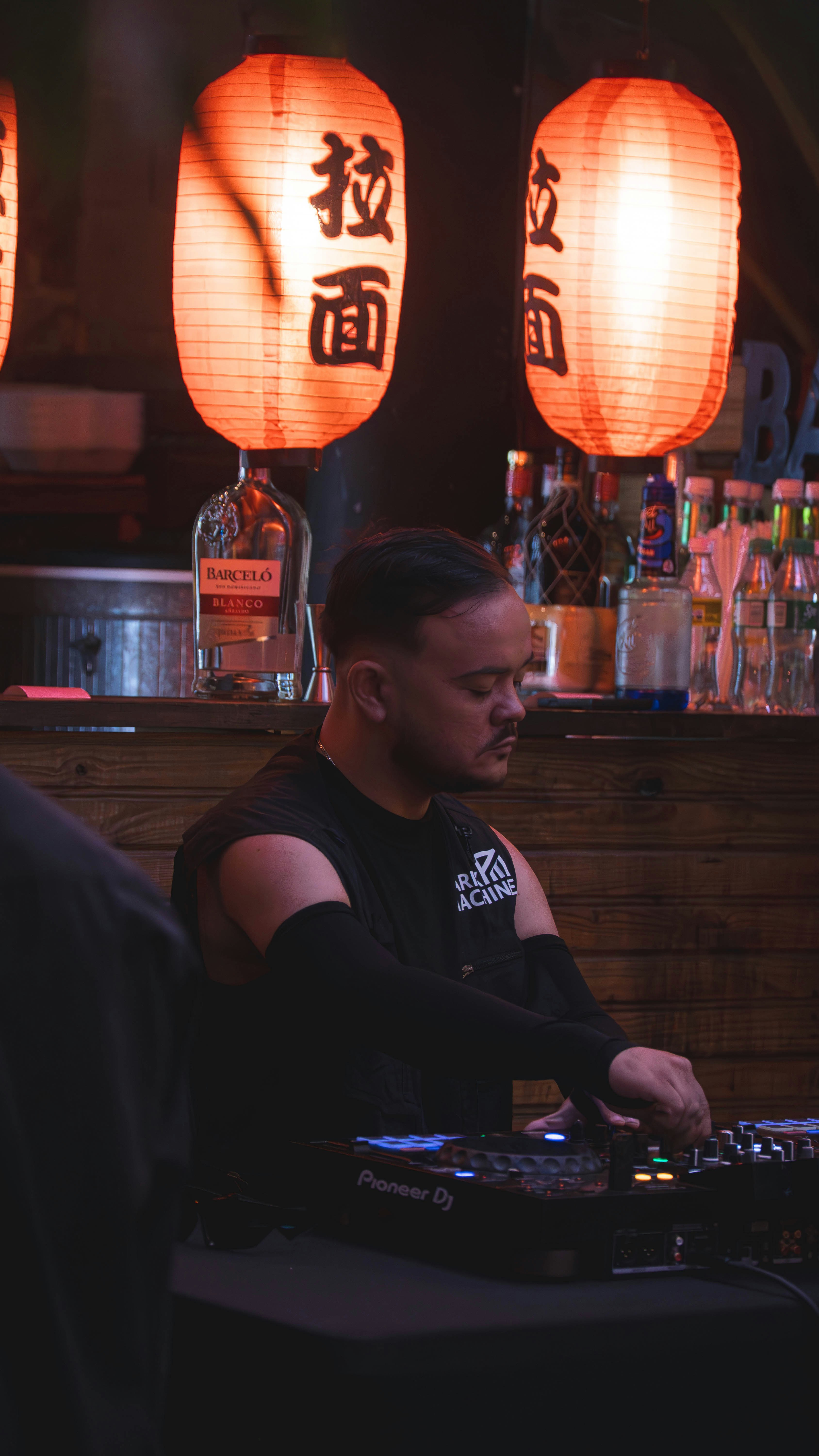 Night Mix: DJ in Red Lantern Glow Behind the Bar