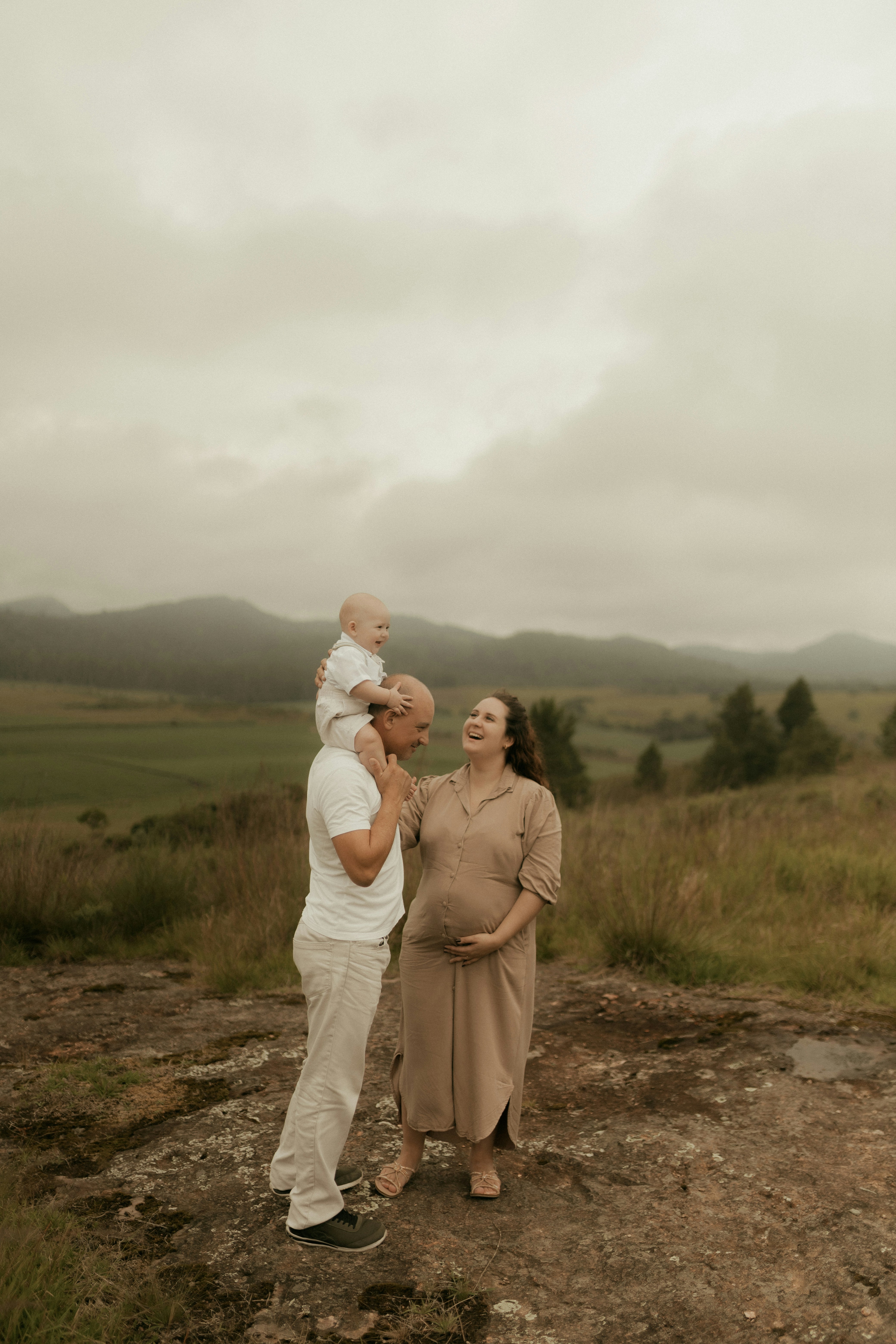 Family on a Golden Field: A Baby’s Laugh Amid Quiet Hills