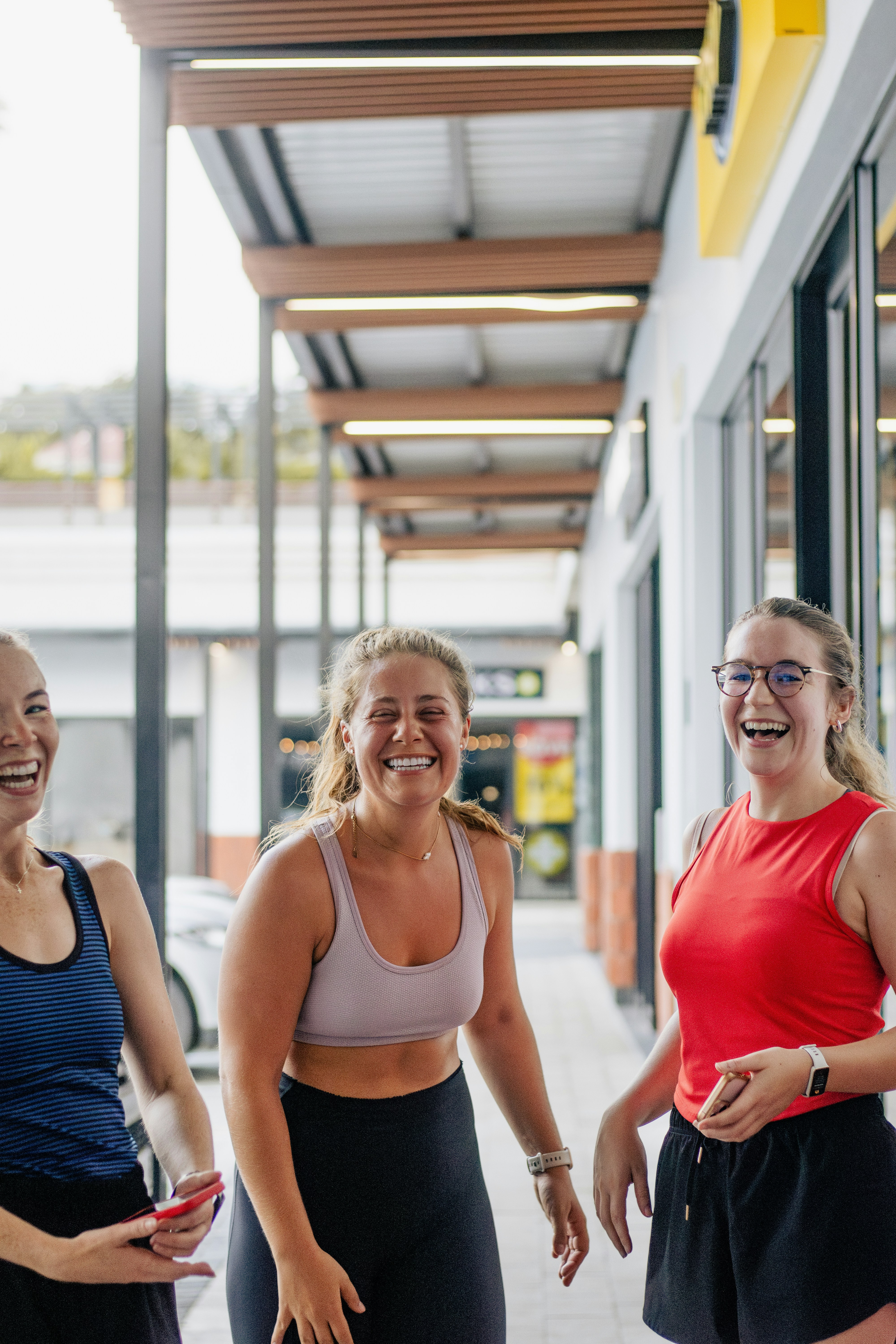 Three Fitness Friends Share a Laughter in a Bright Shopping Arcade