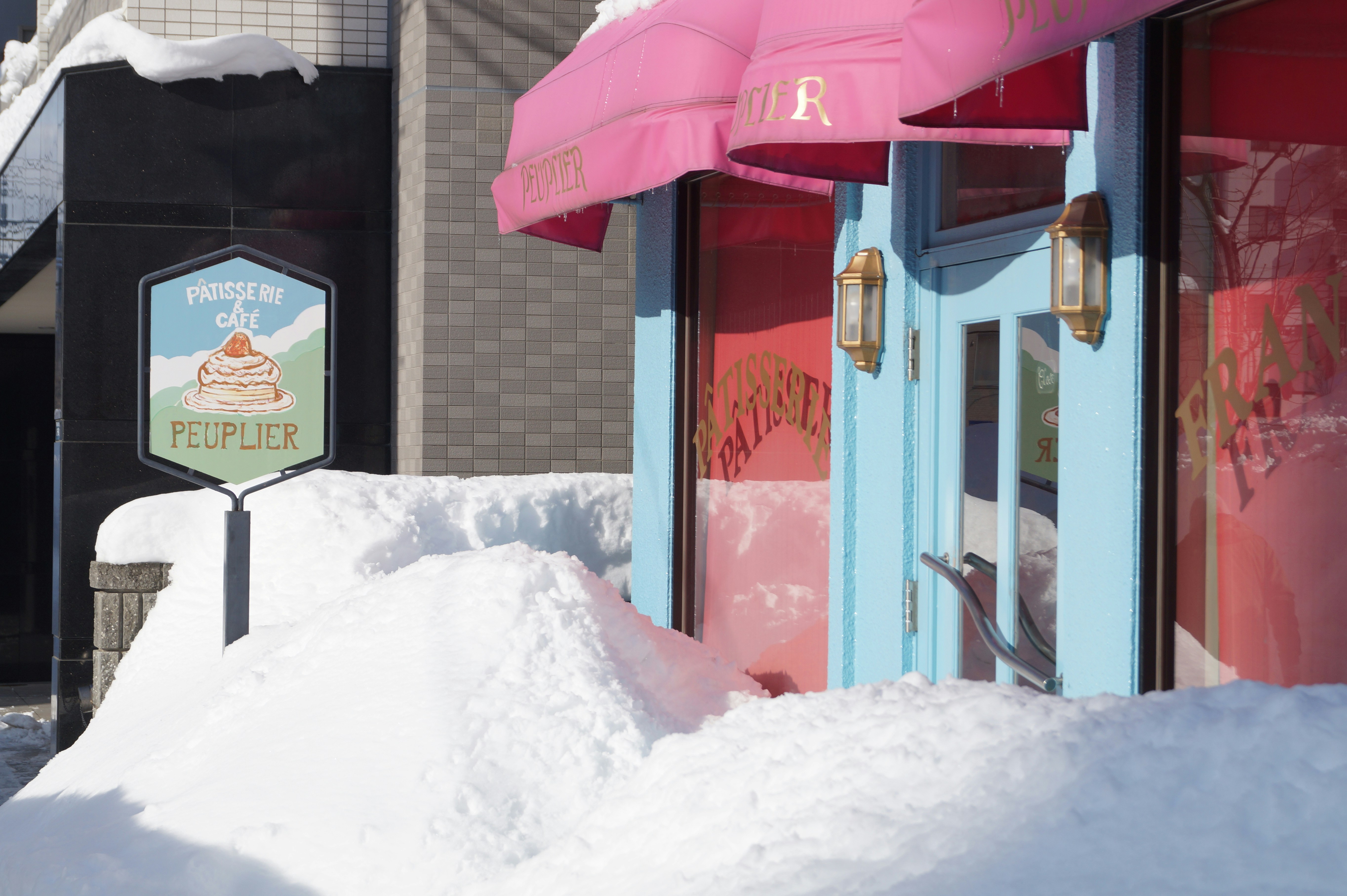 Pink Canopy Over Snowy storefront with French Pastry Sign