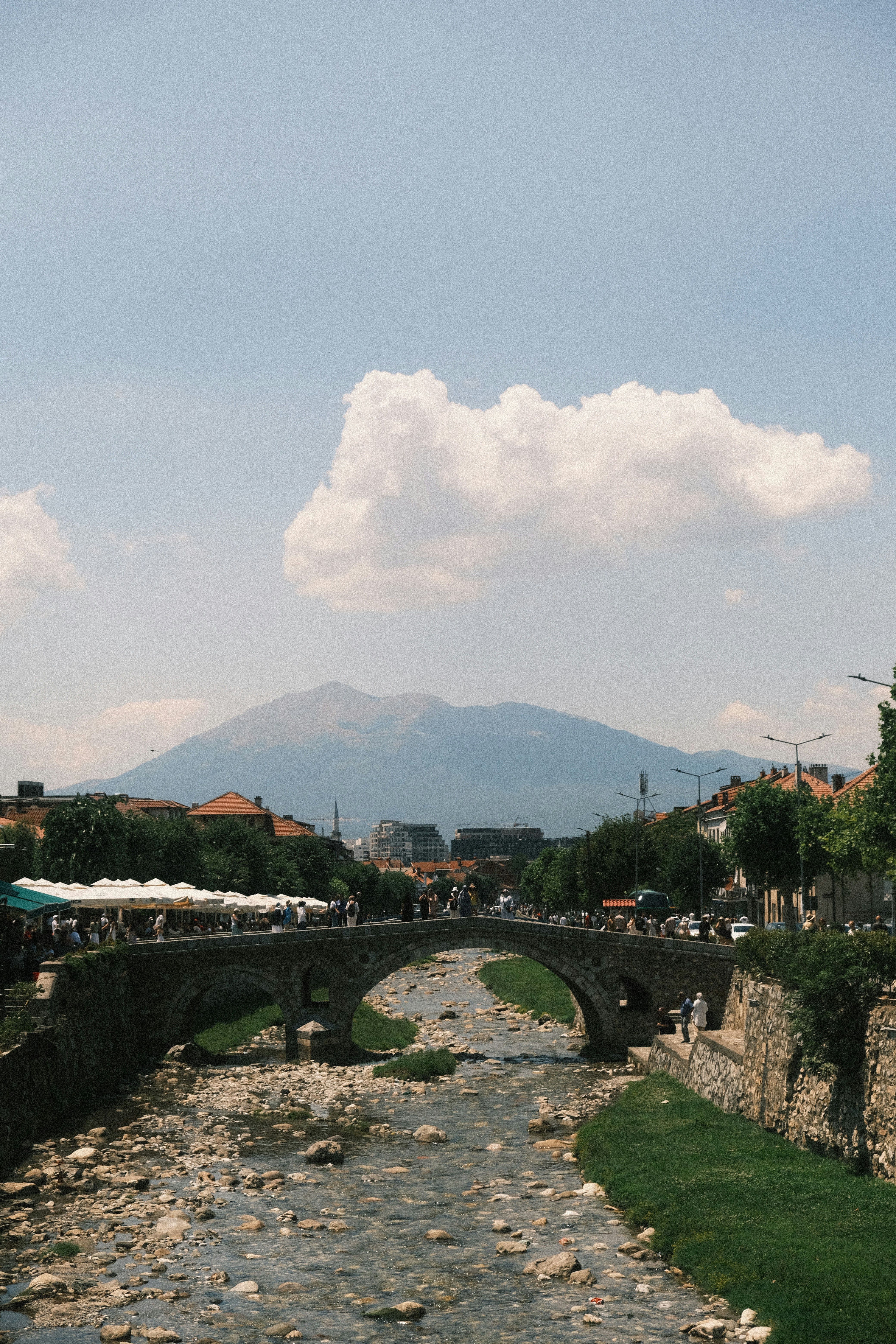 Stone Bridge over a Shallow River with Mountain Backdrop