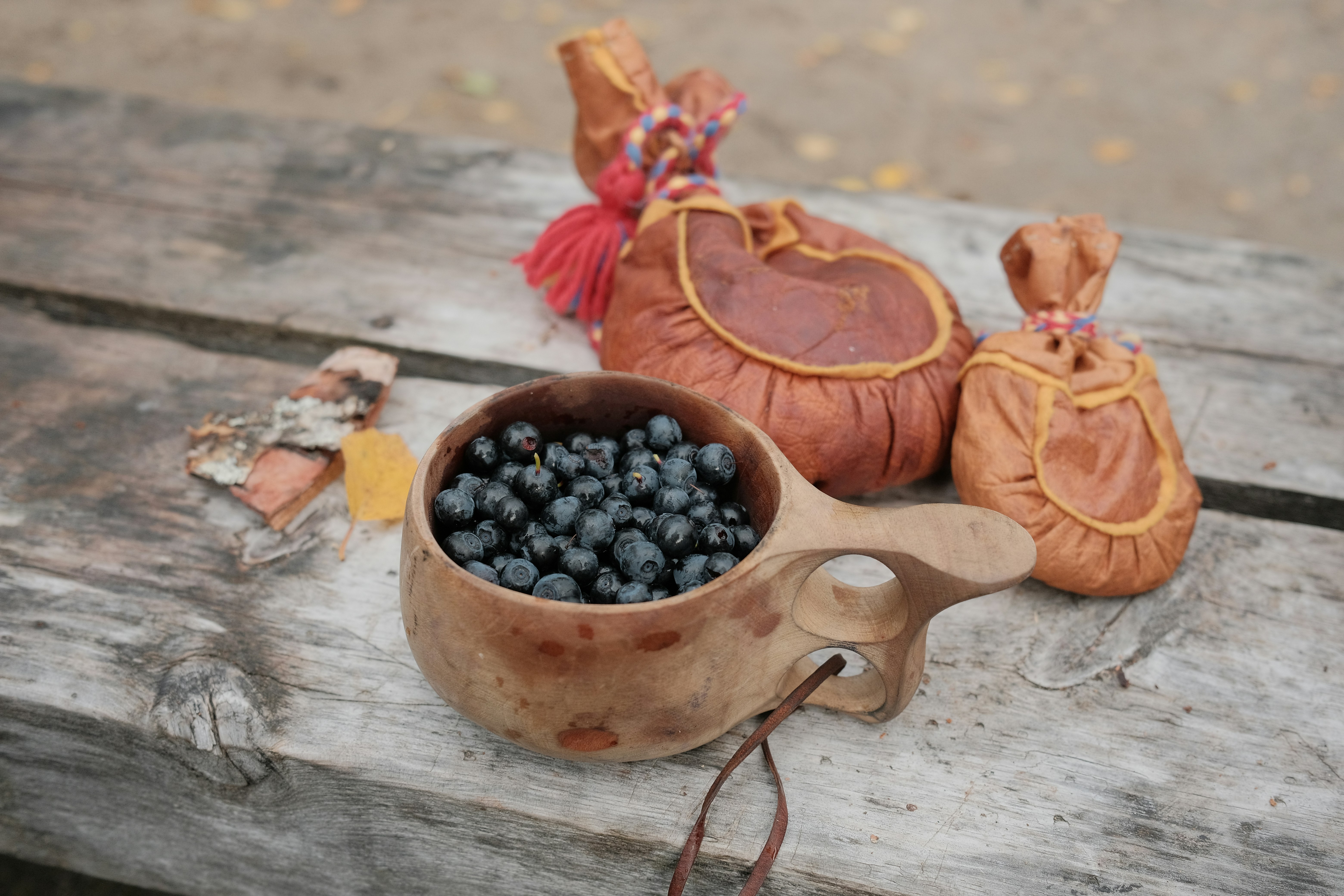 Cozy Still Life: Dark Berries in a Handled Cup with Rustic Sacks on Weathered Wood
