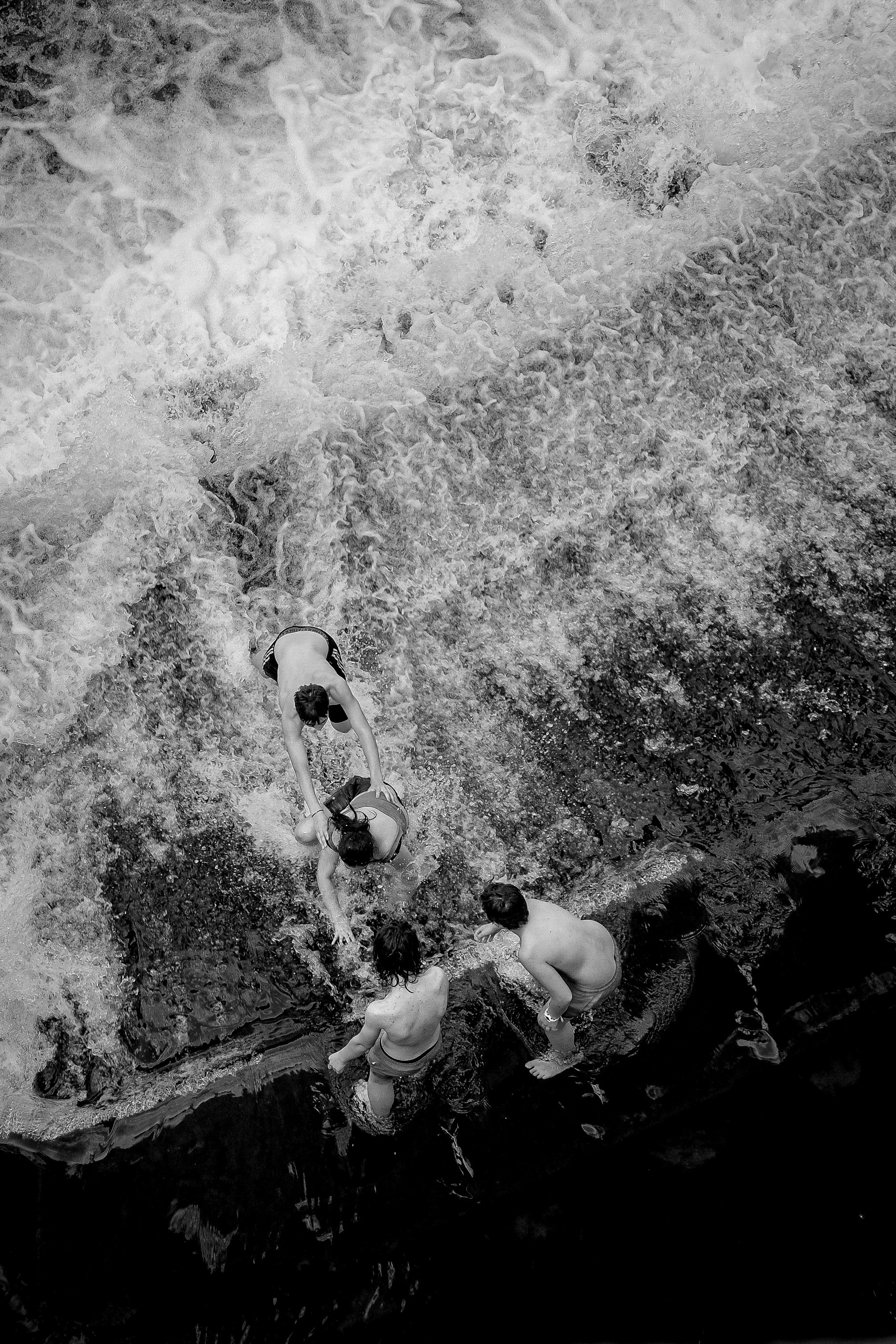 Top-Down Splash: A Pair of Swimmers Surrounded by Foam on a Dark Shore