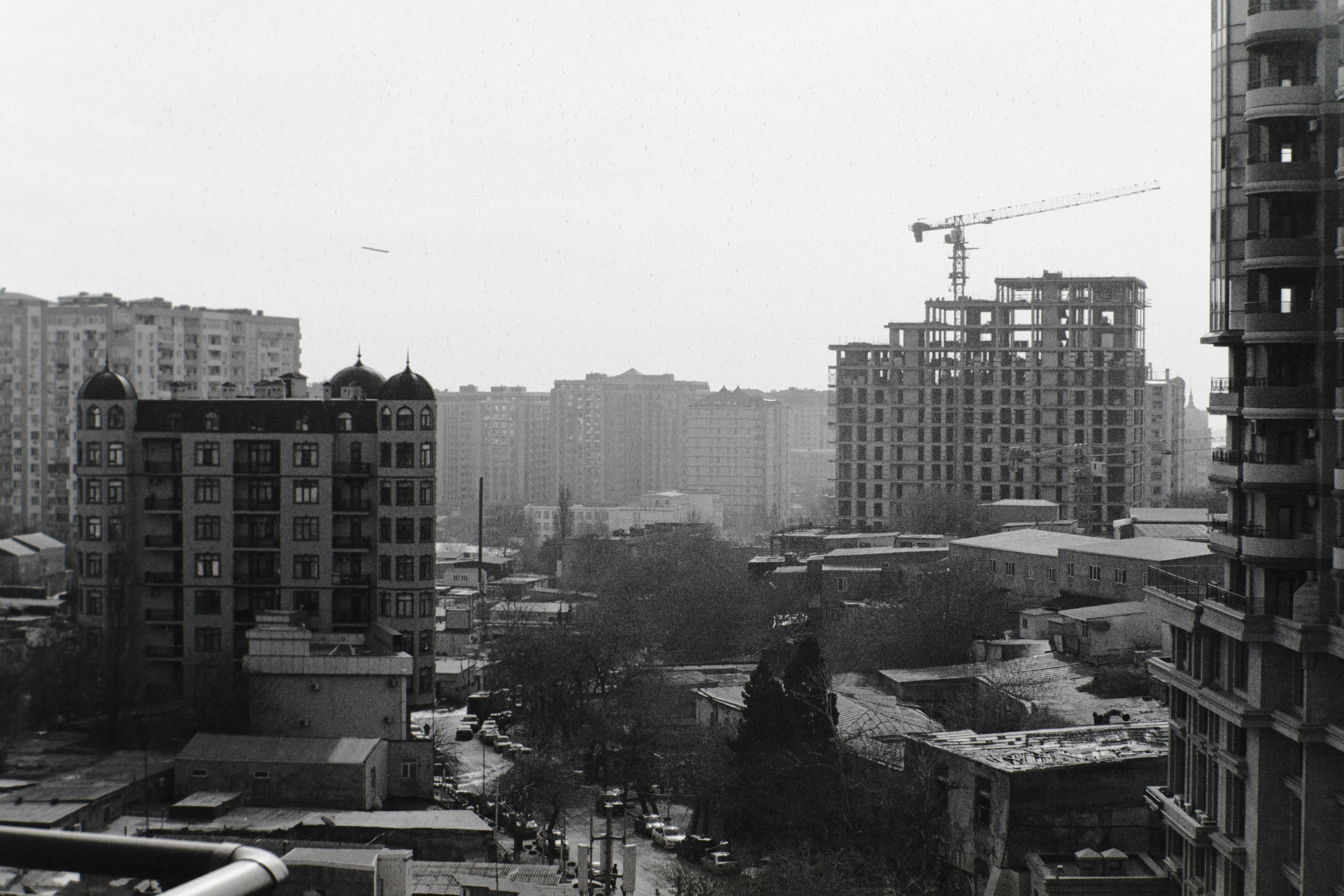 Urban Gravity: Crane Silhouettes Above Distant Towers