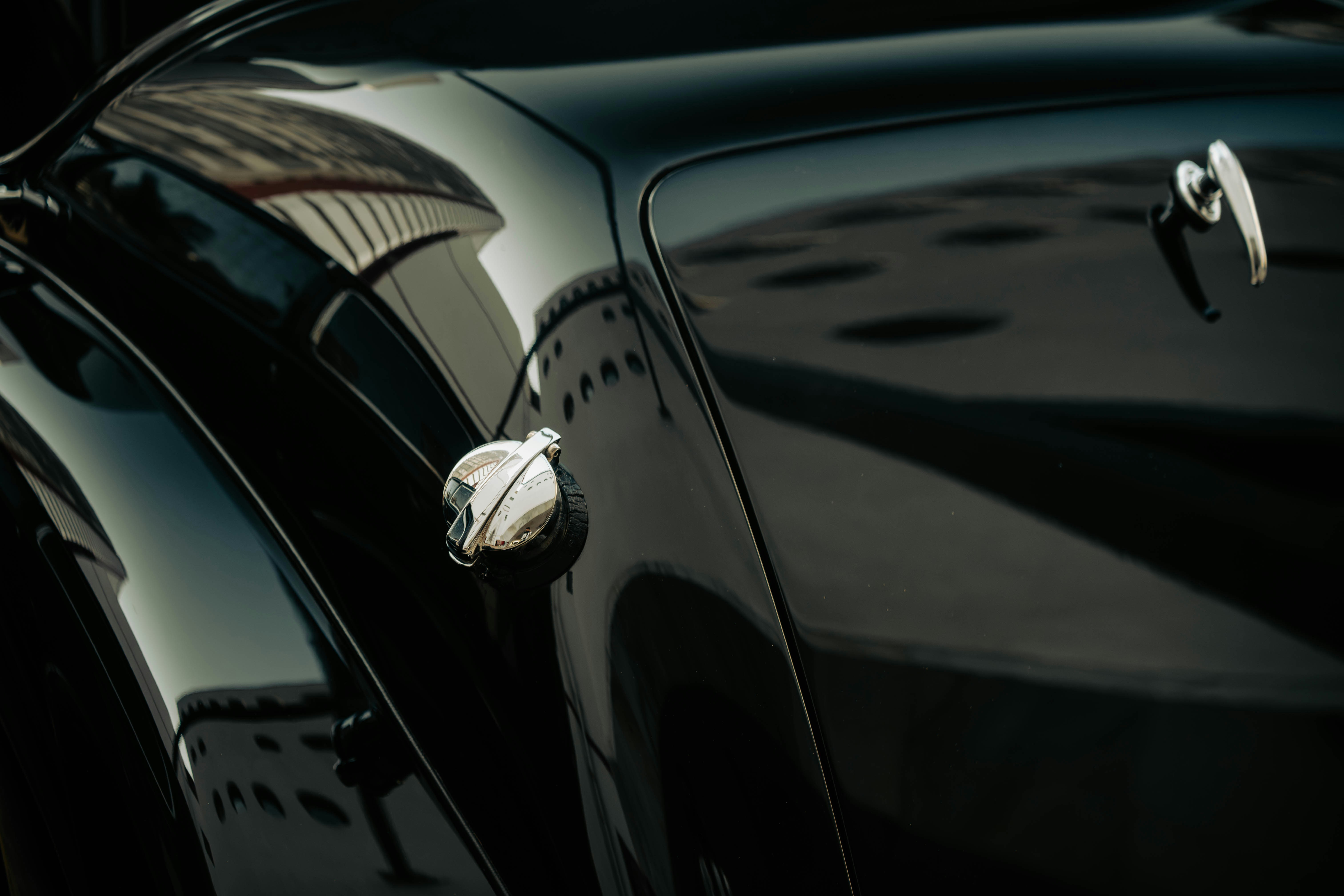 Close-up of a classic car's shiny black fender.