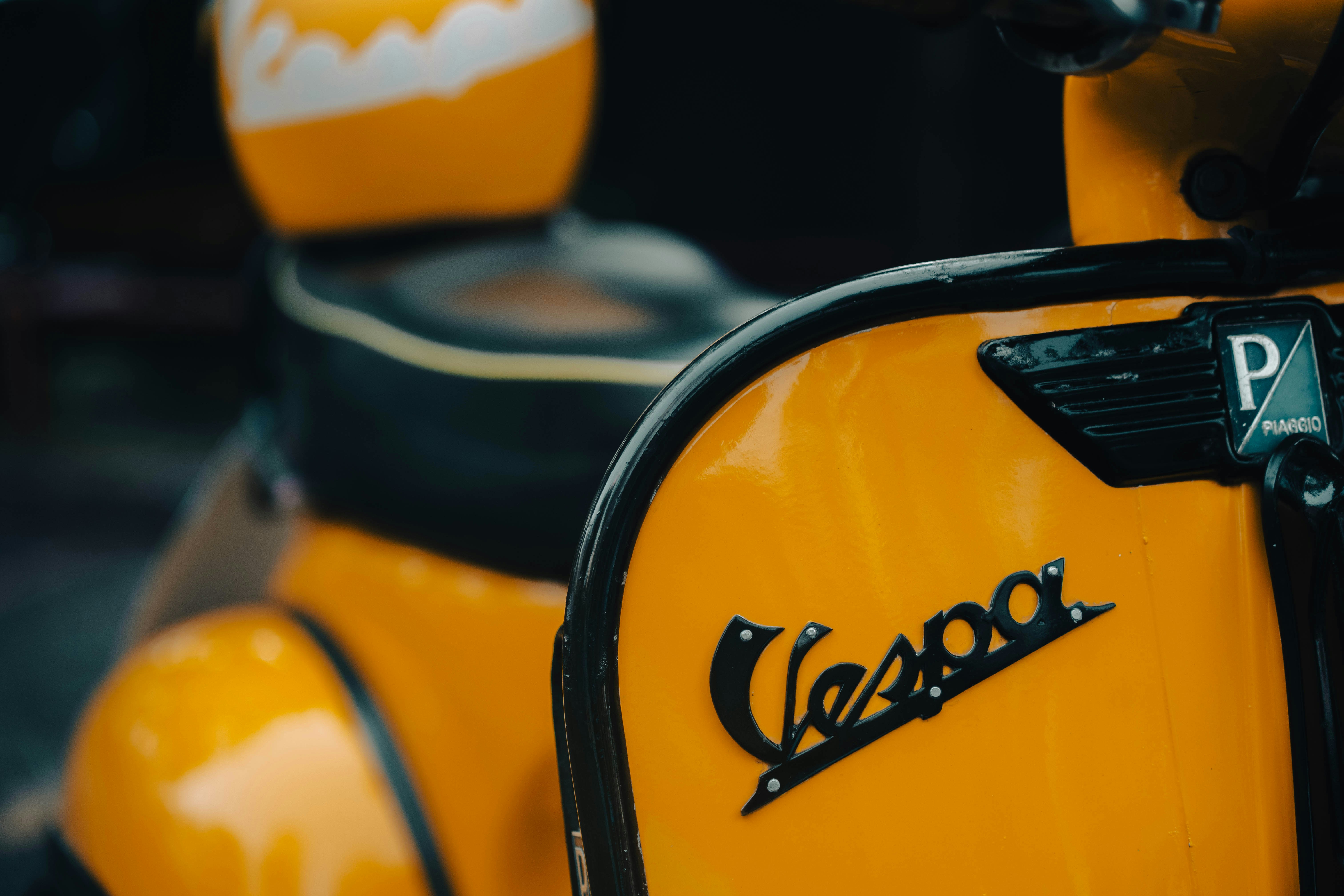 A bright yellow vespa scooter with black accents.
