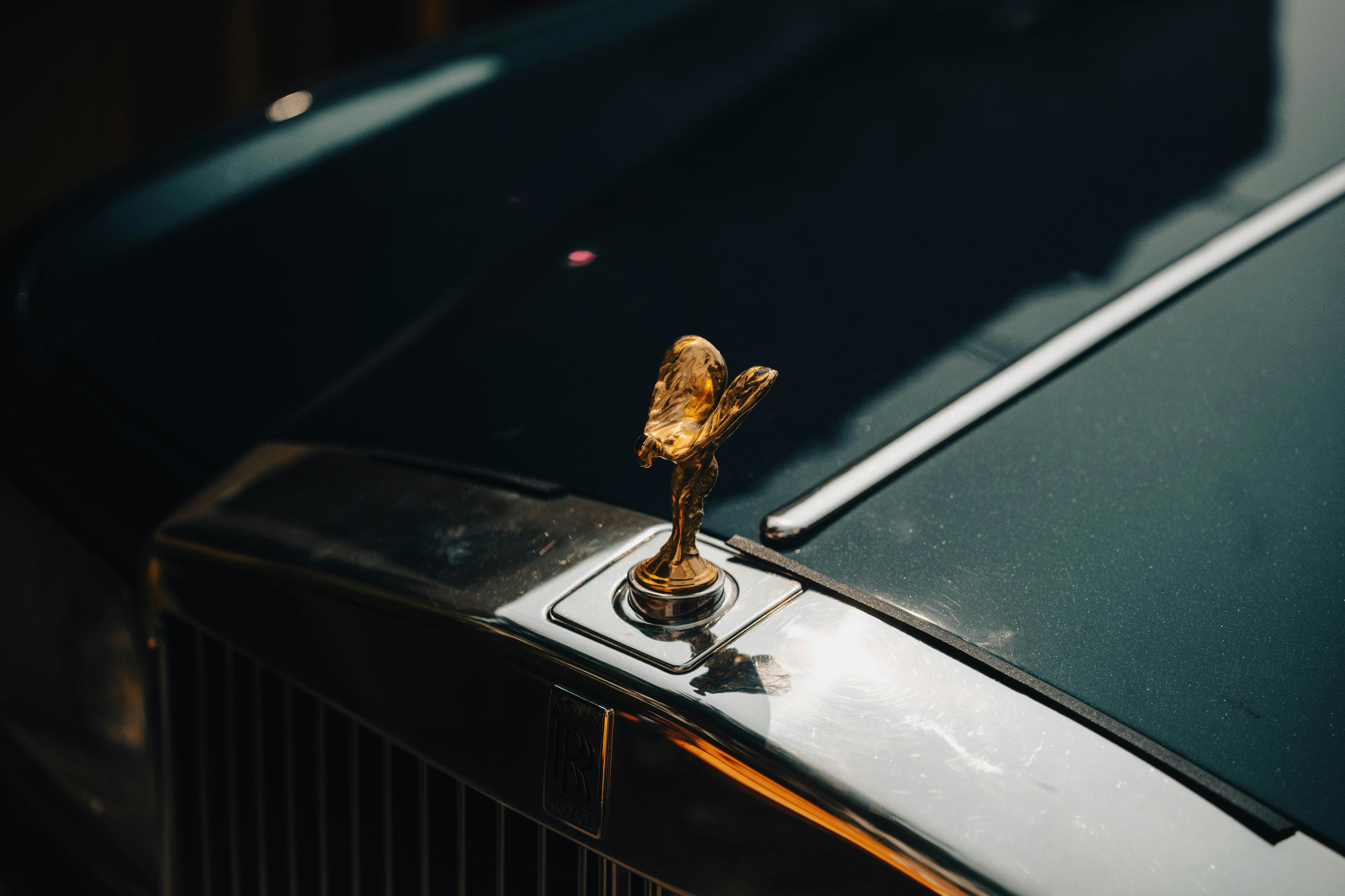 Golden hood ornament on a dark luxury car