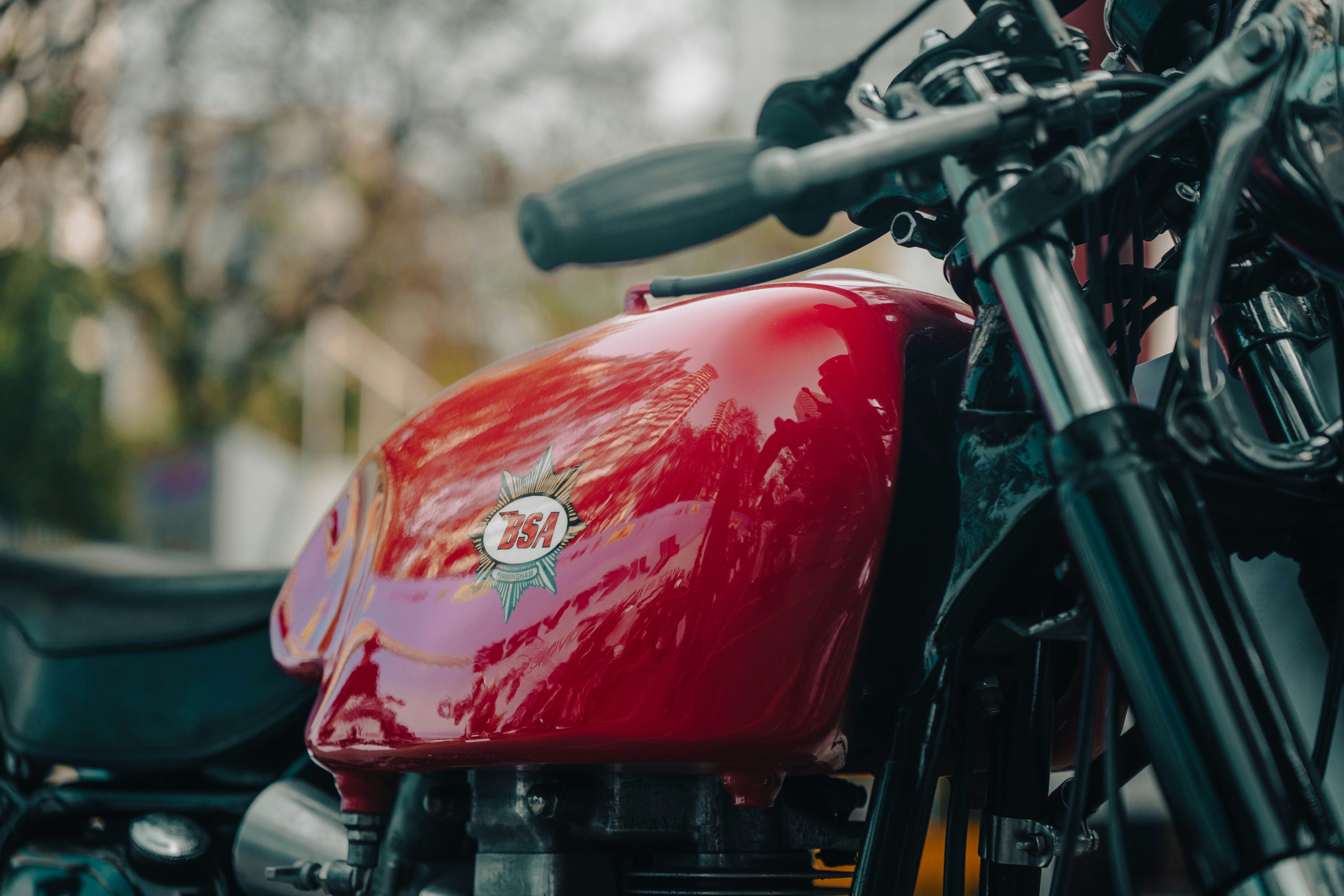 Close-up of a shiny red vintage motorcycle fuel tank.