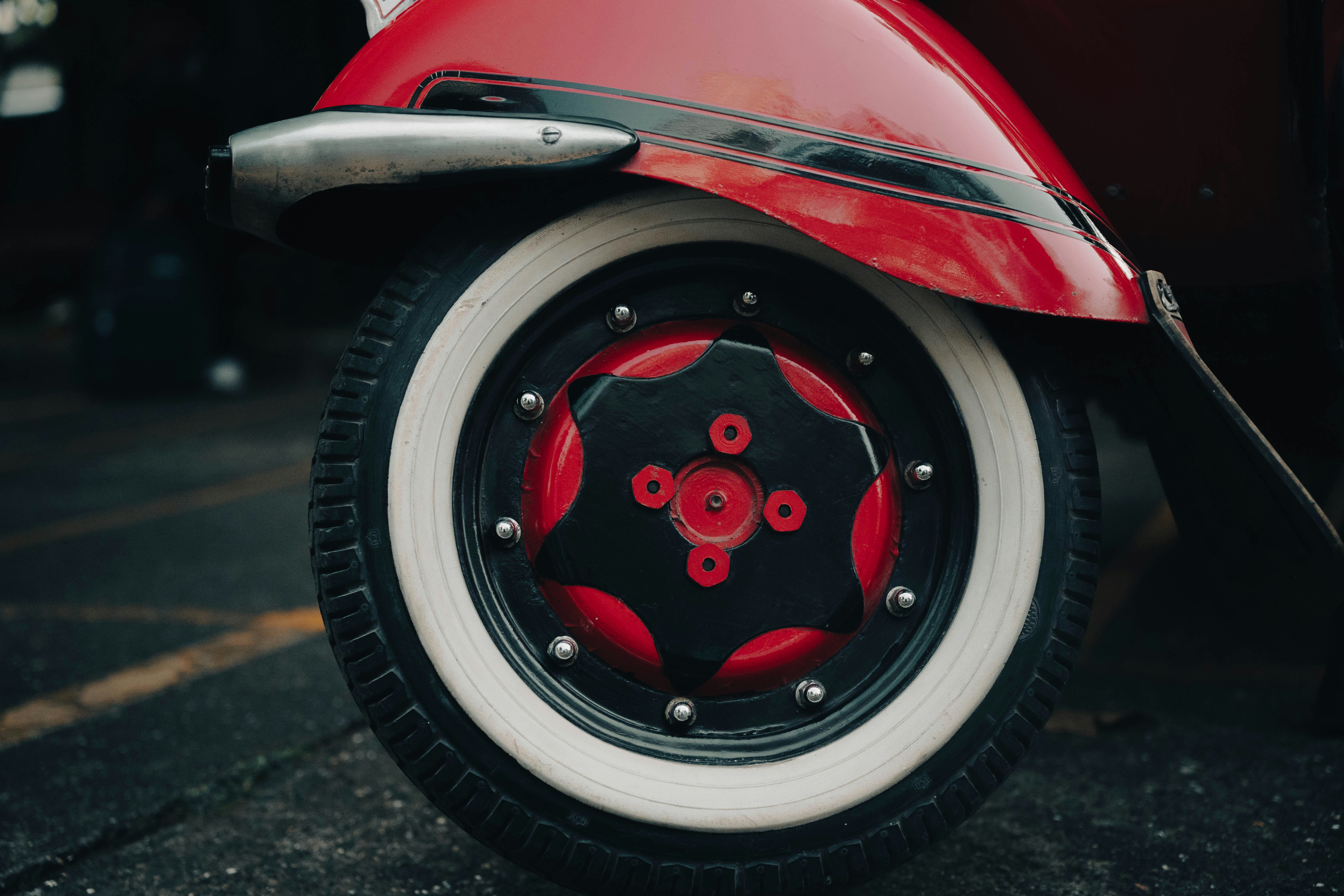 Close-up of a red vintage scooter wheel with white tire.