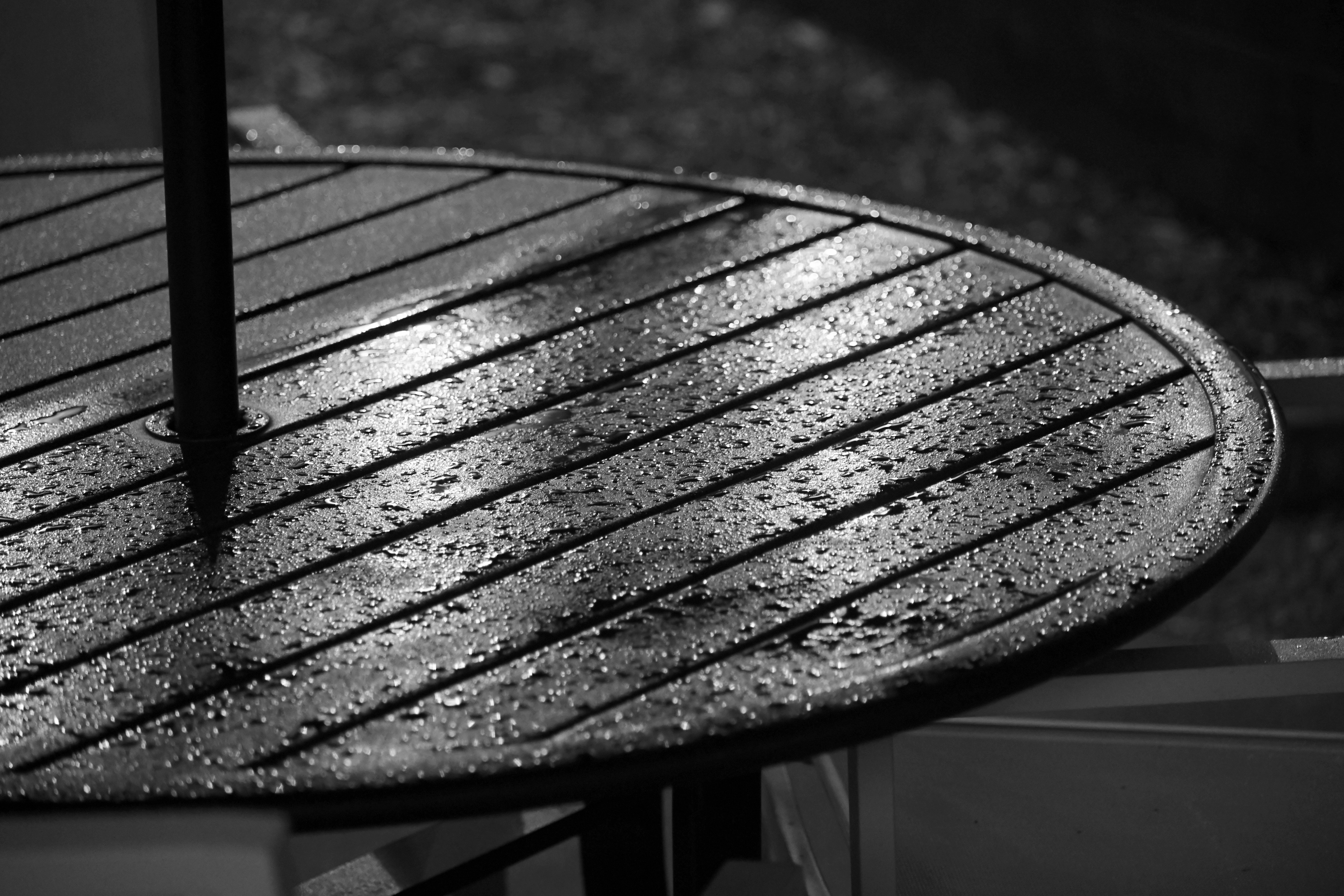 Dew-Kissed Grill: Quiet Geometry of Rainy Light on a Patio Table