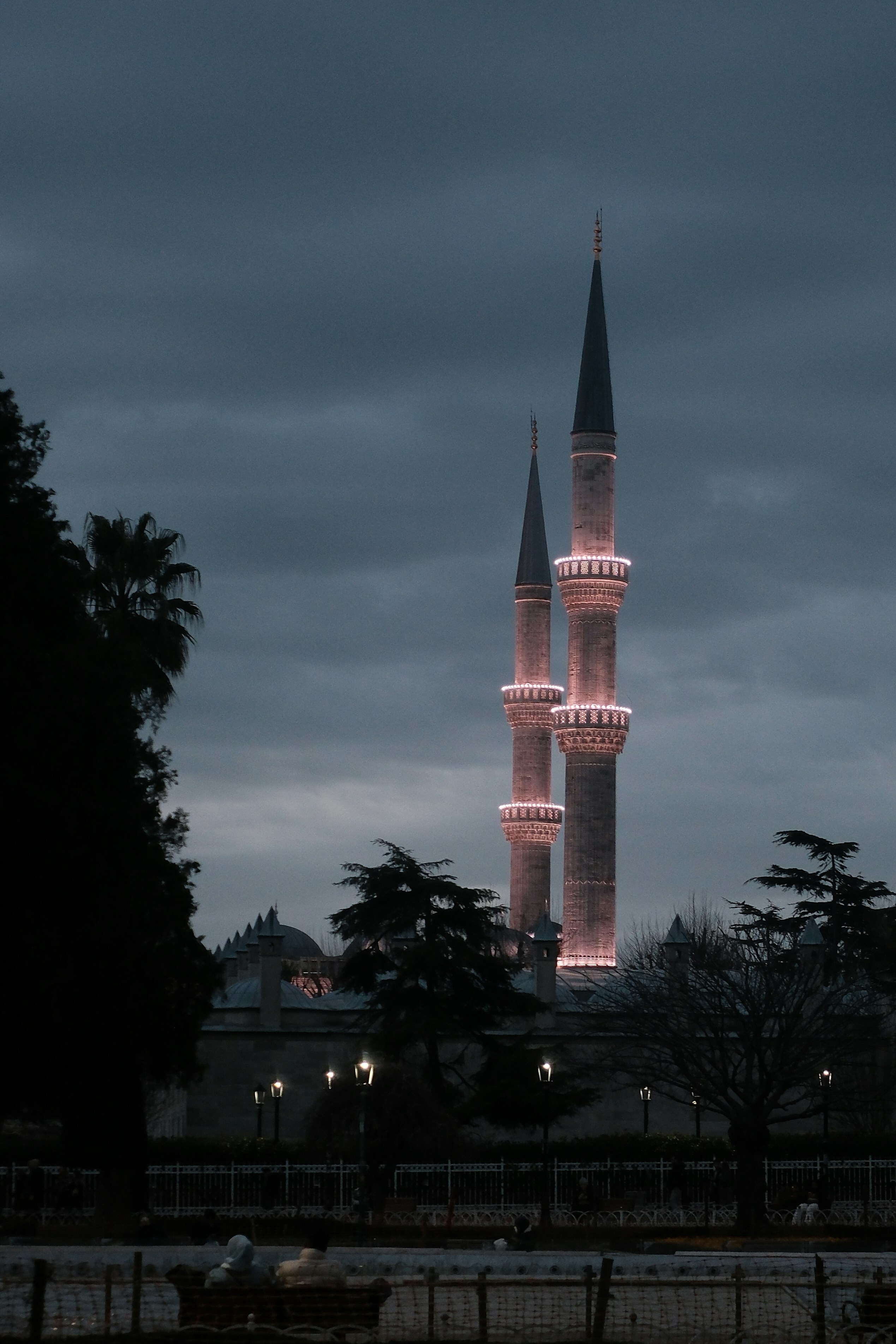 Twin Minarets at Dusk: Illuminated Spires Rise Over a Quiet City Park