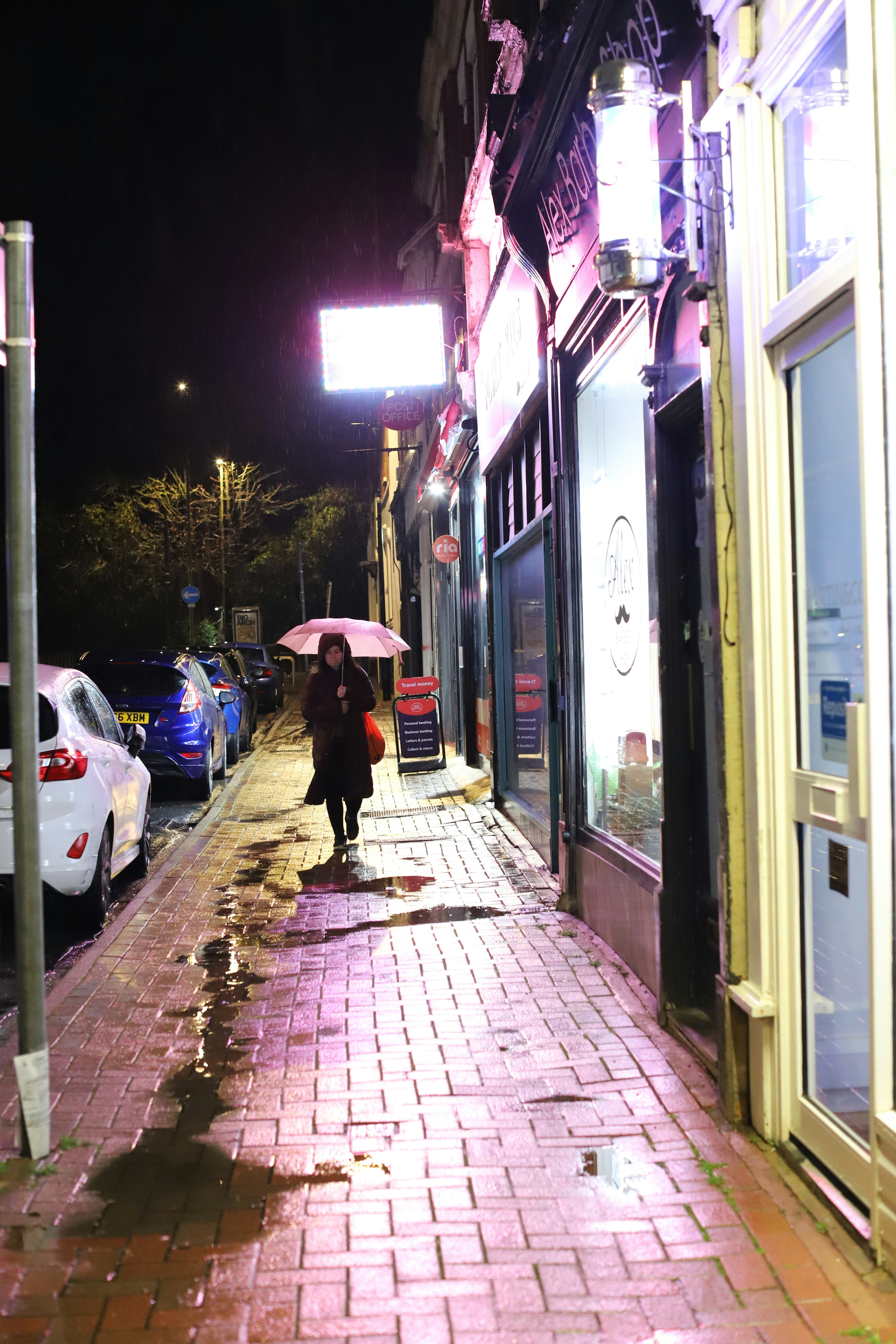 Night Rain, Neon Sidewalk: A lone figure with a pink umbrella