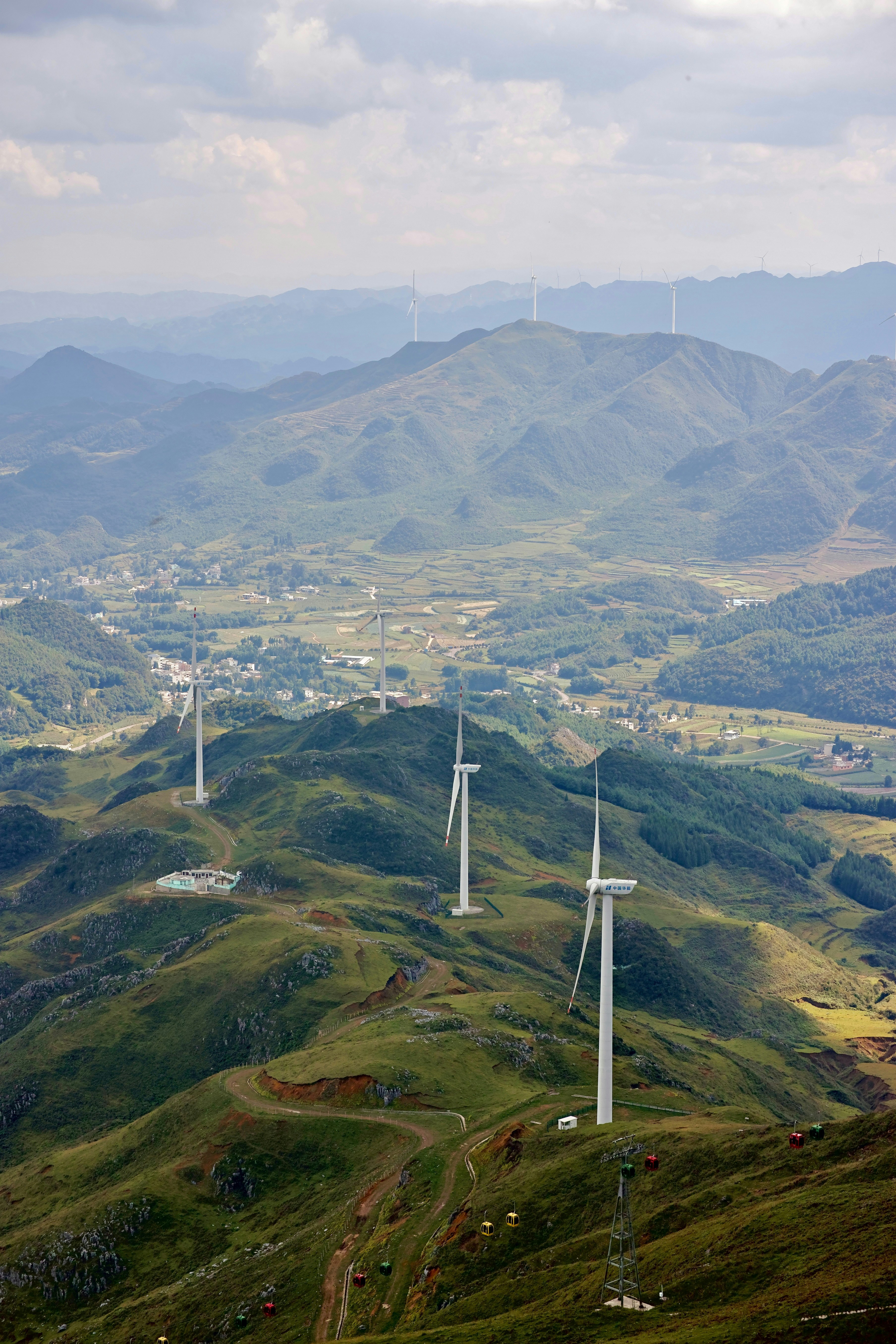 Wind turbines on rolling green hills with a village below