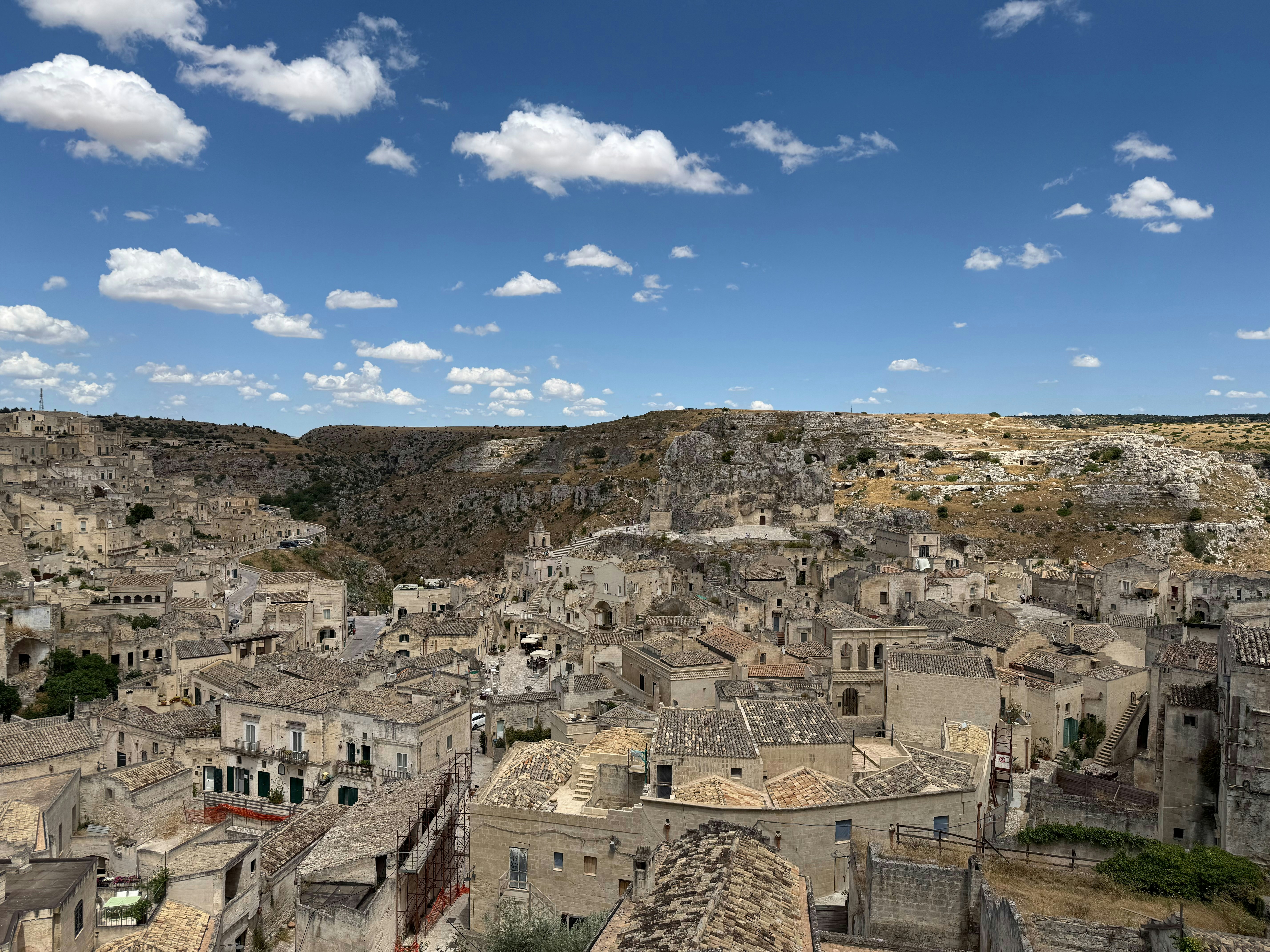 Stone Labyrinth: Aerial view of weathered ancient town tucked beneath a cloud-dotted sky