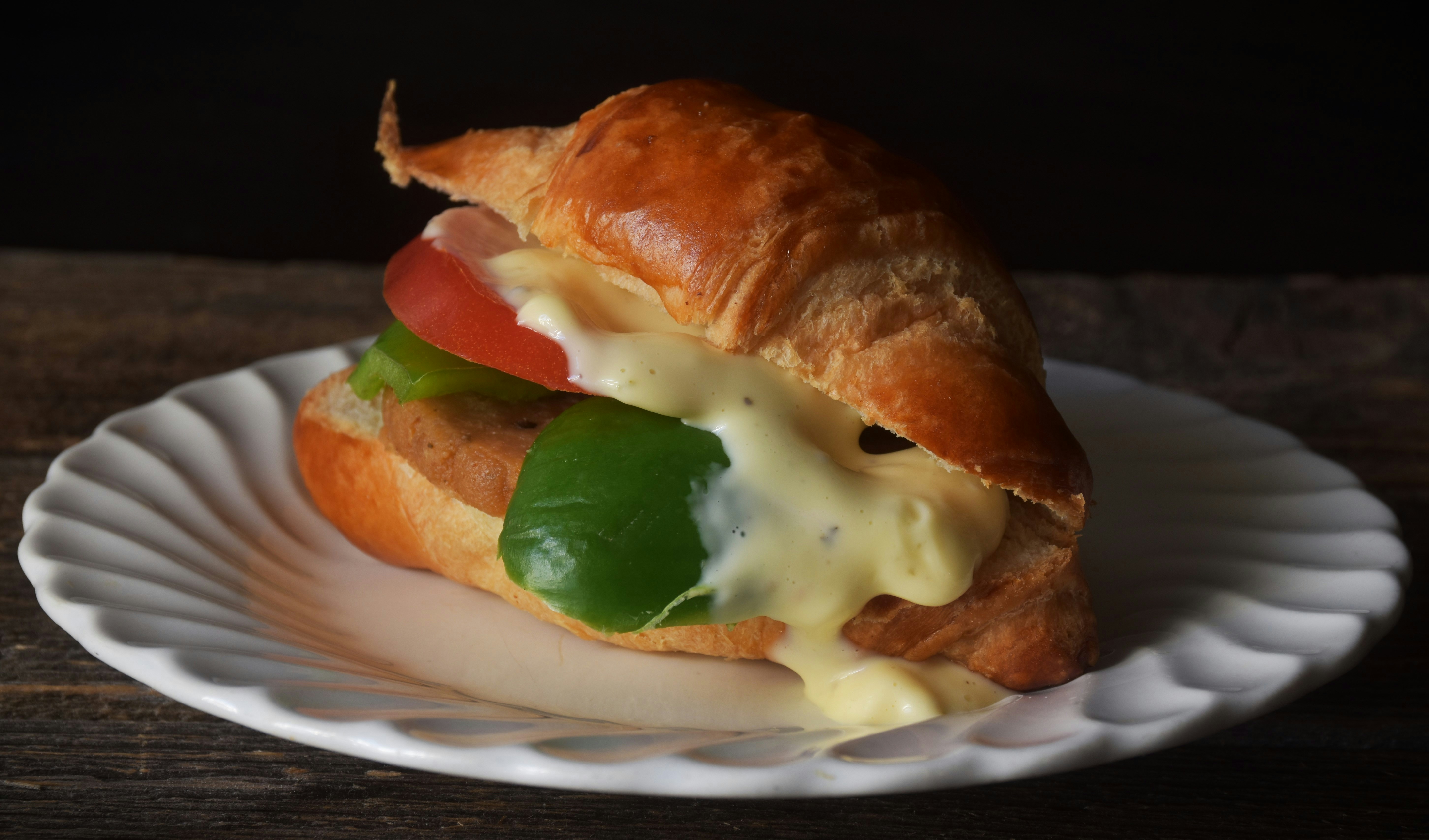 Creamy Melt: A Crispy Croissant Sandwich with Fresh Veggies On a Rustic Plate