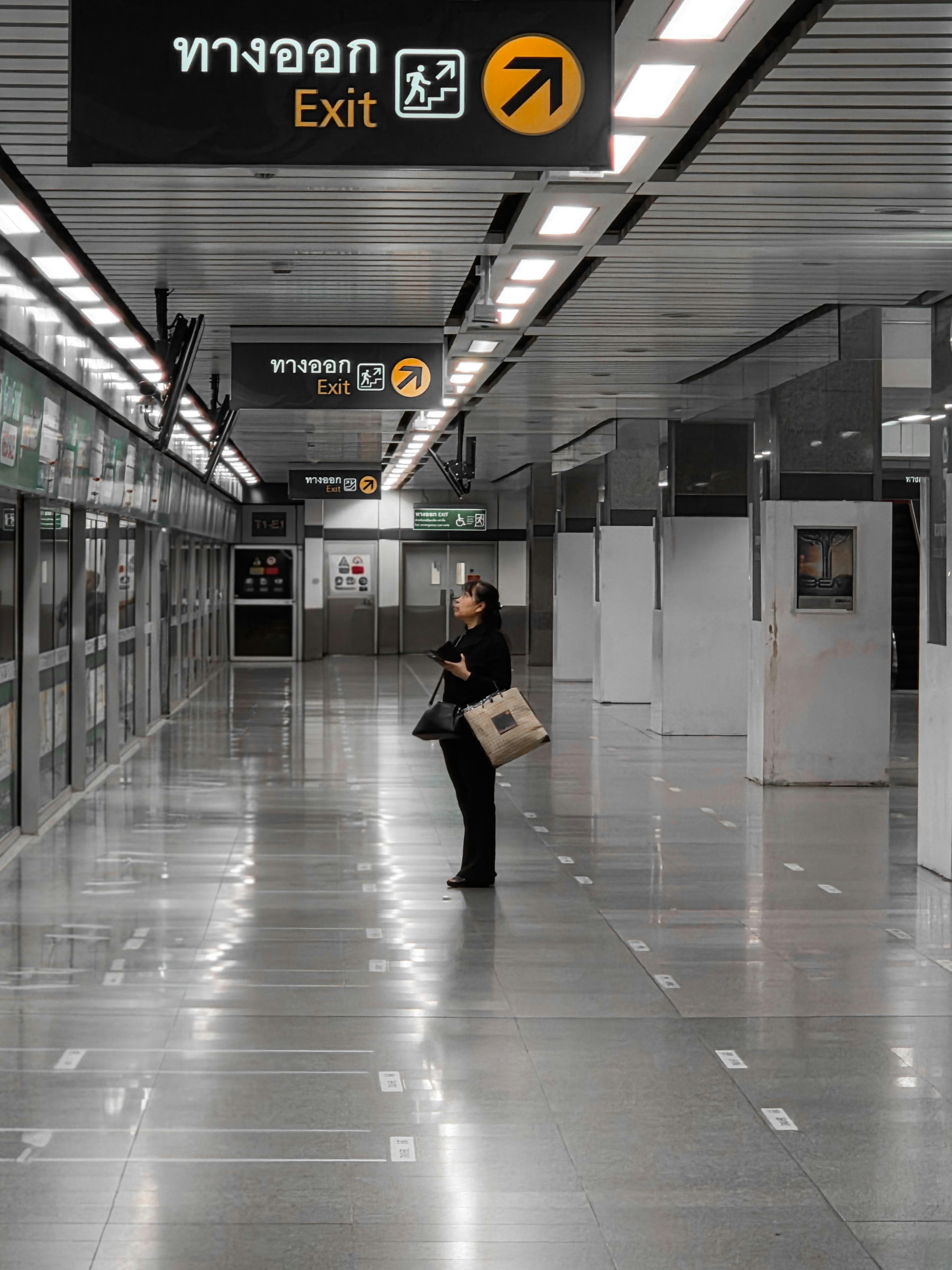 A random woman checks the overhead signage at a modern subway station in Bangkok, Thailand.