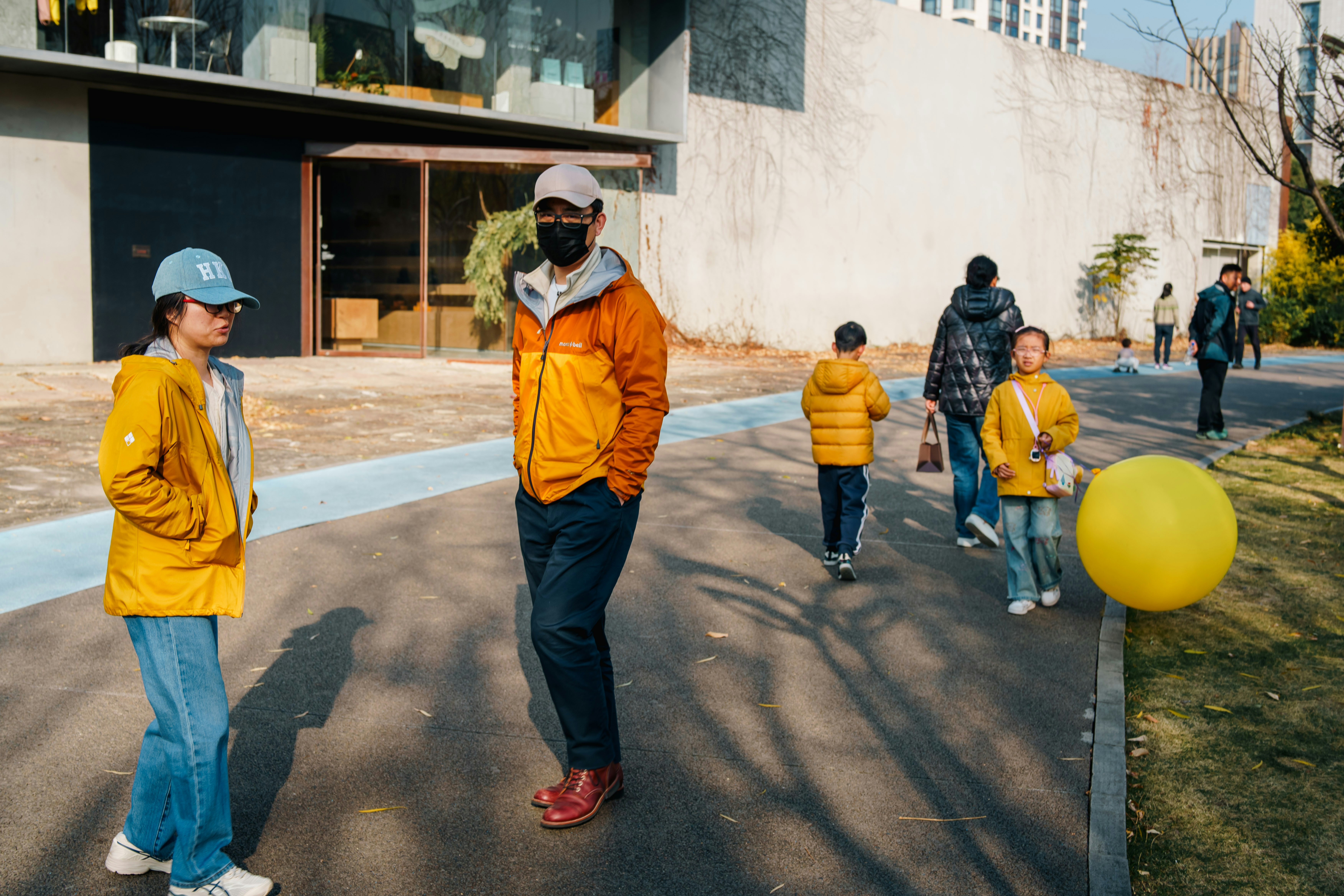 Yellow jackets and a bright ball at a sunlit campus courtyard