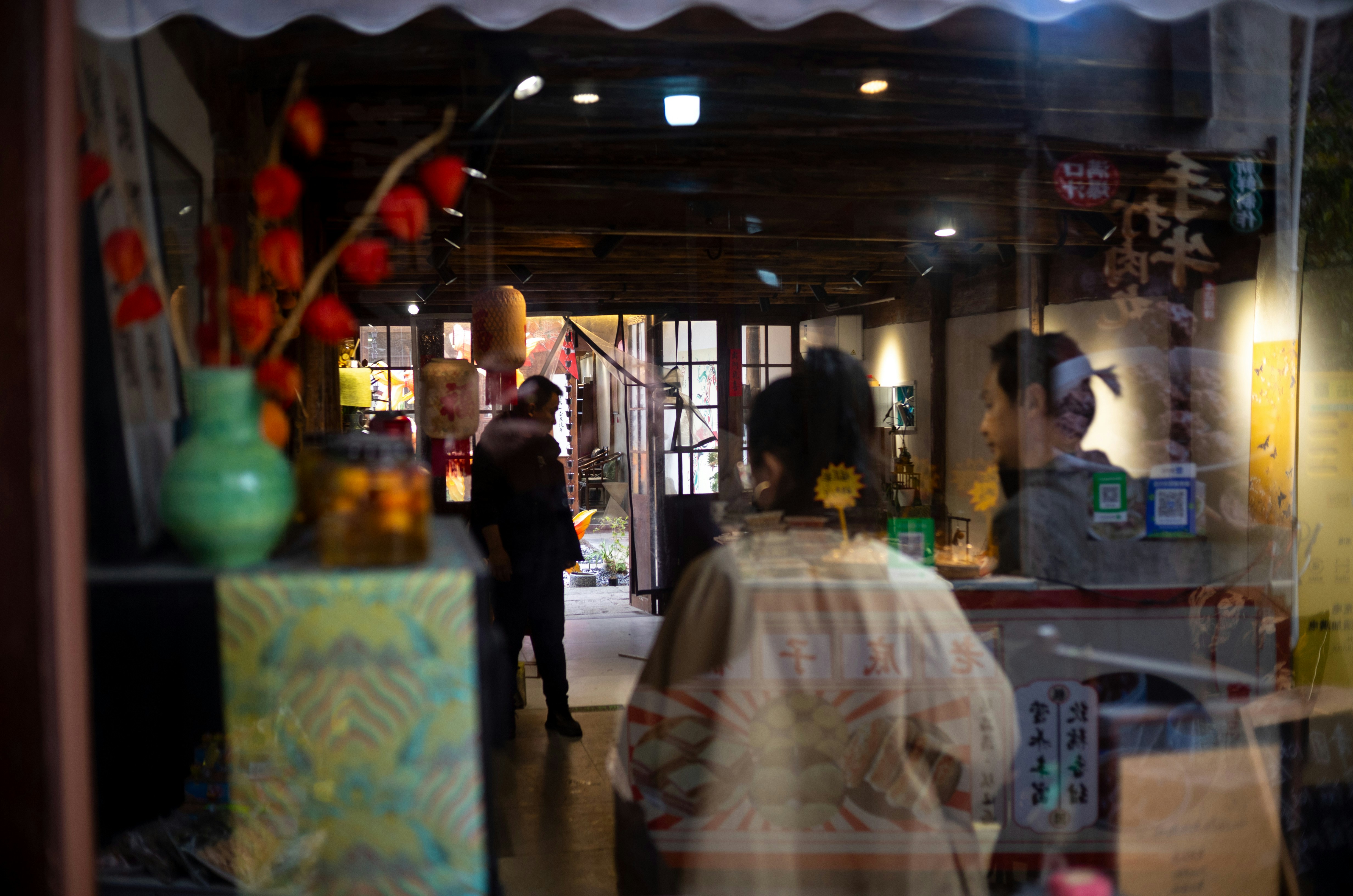 People walk through a dimly lit shop interior.