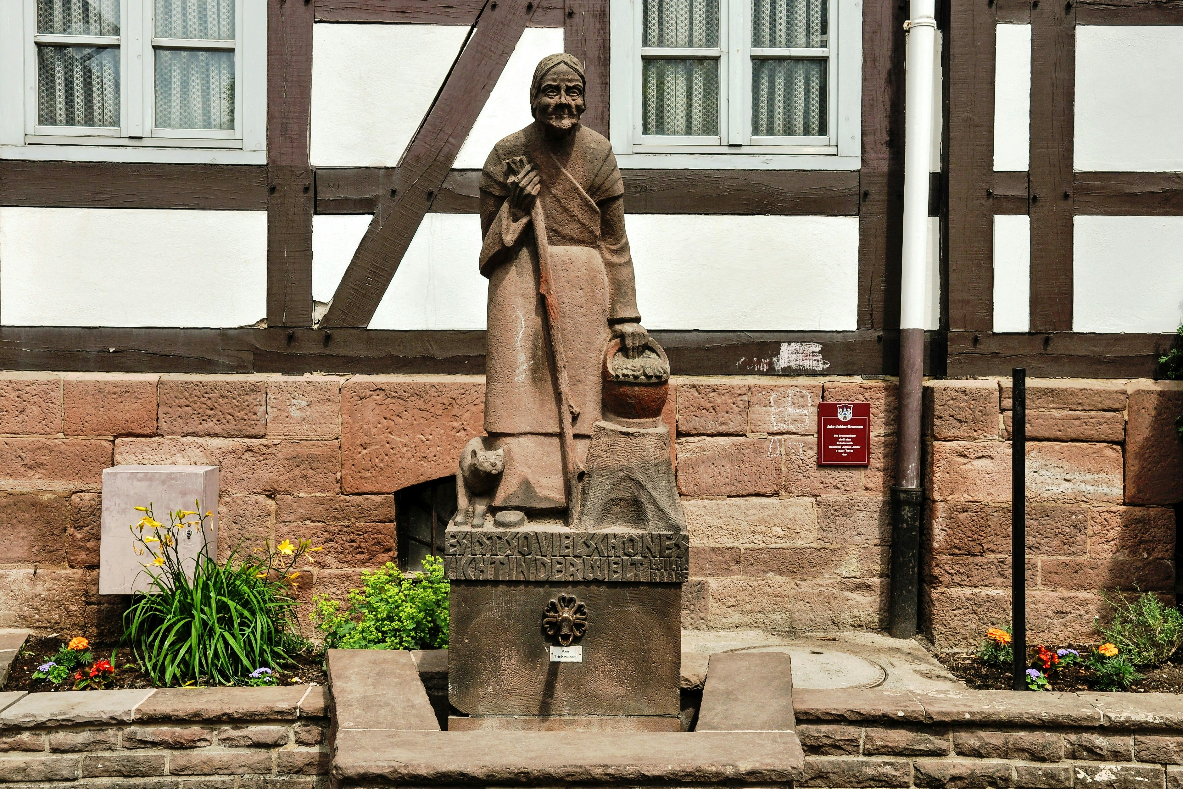 Stone Shrine Figure: A Timeless Witness at a Timber-Framed Courtyard
