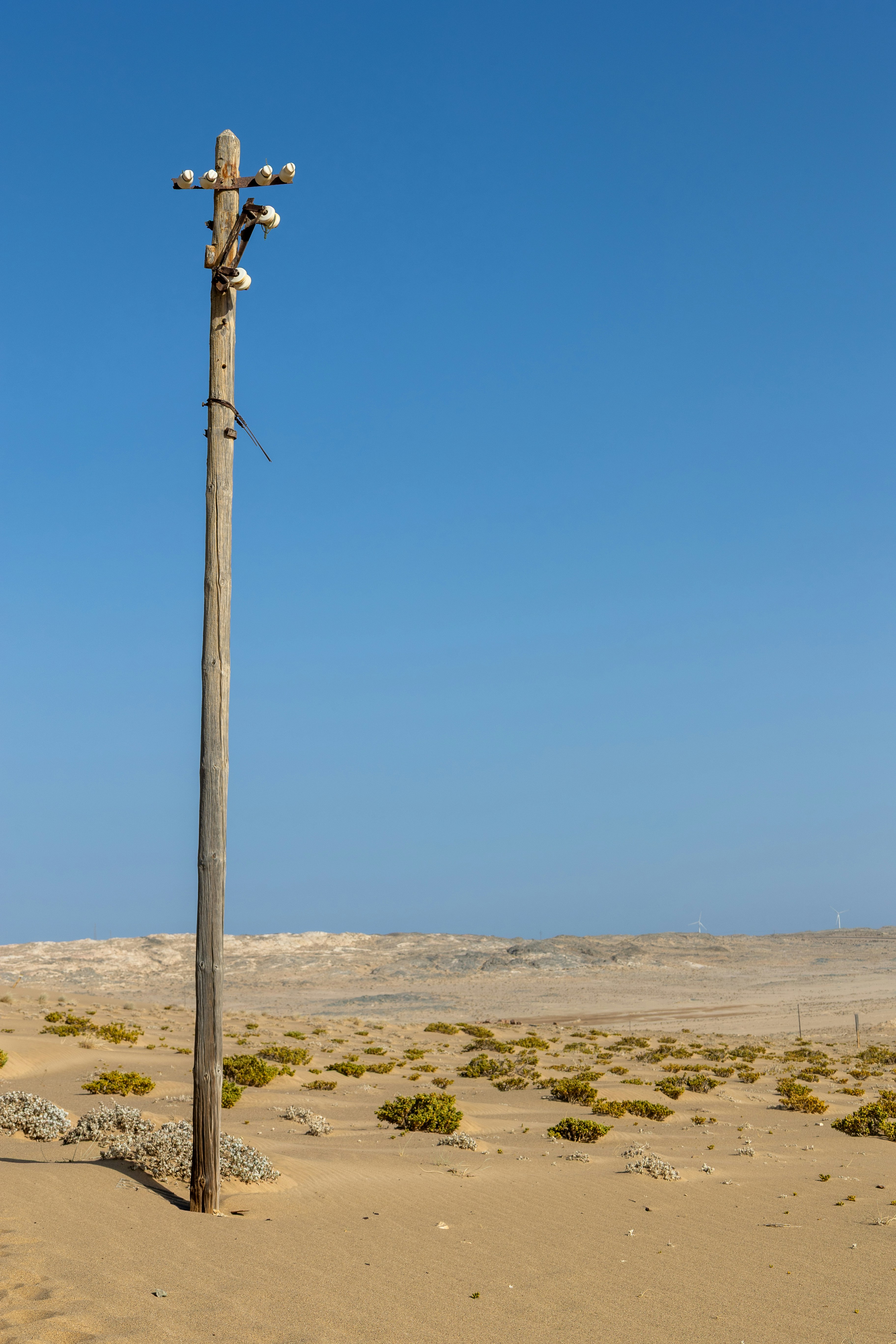 Desert Sentinel: A Lone Utility Post Against a Vast Blue Sky
