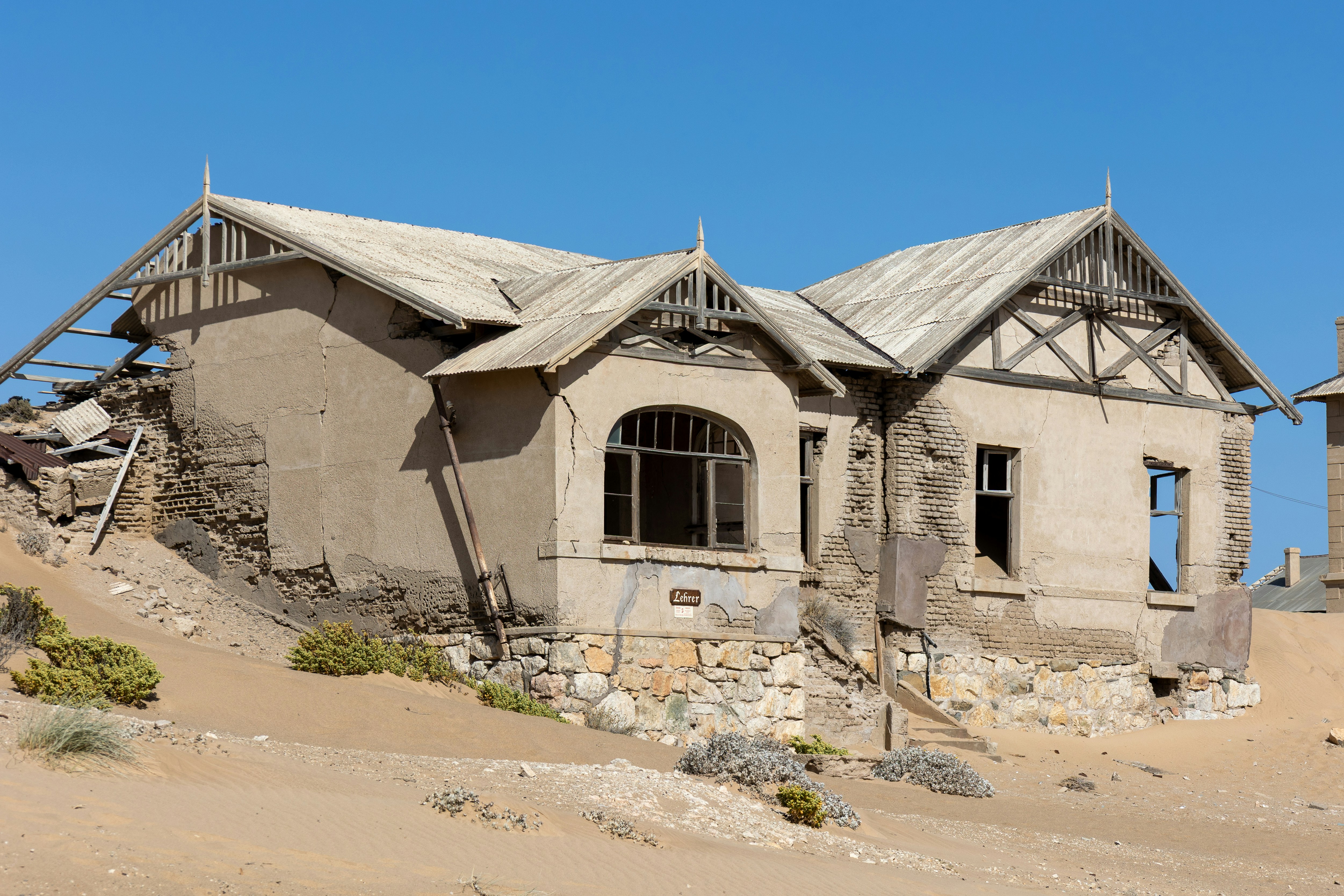 Deserted adobe house leaning into the wind and sun