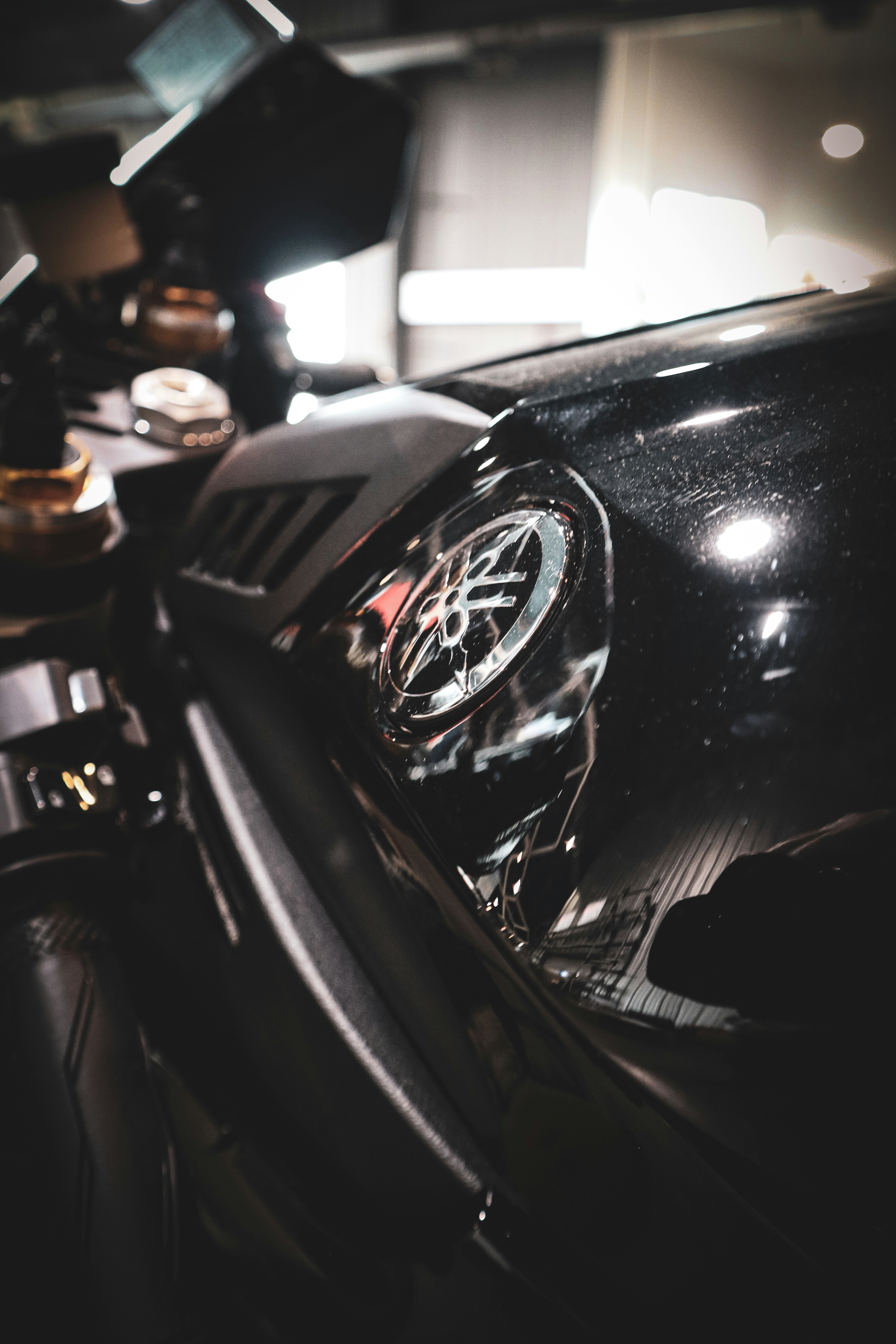 Chrome Crown: A Close-Up of a Yamaha Bike’s Fuel Tank Emblem in Dim Booth Light