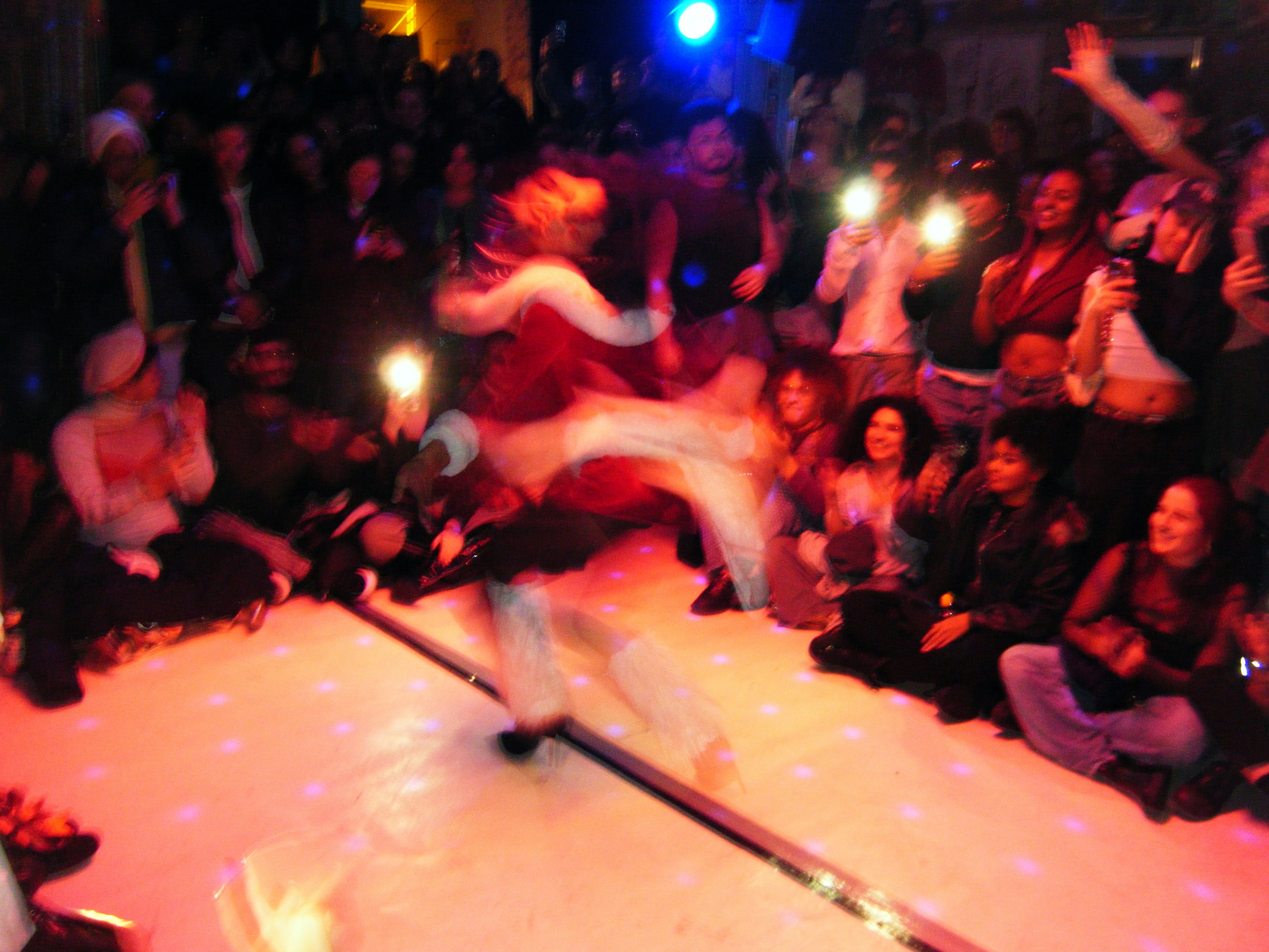 People watching a dance performance in a dimly lit room.