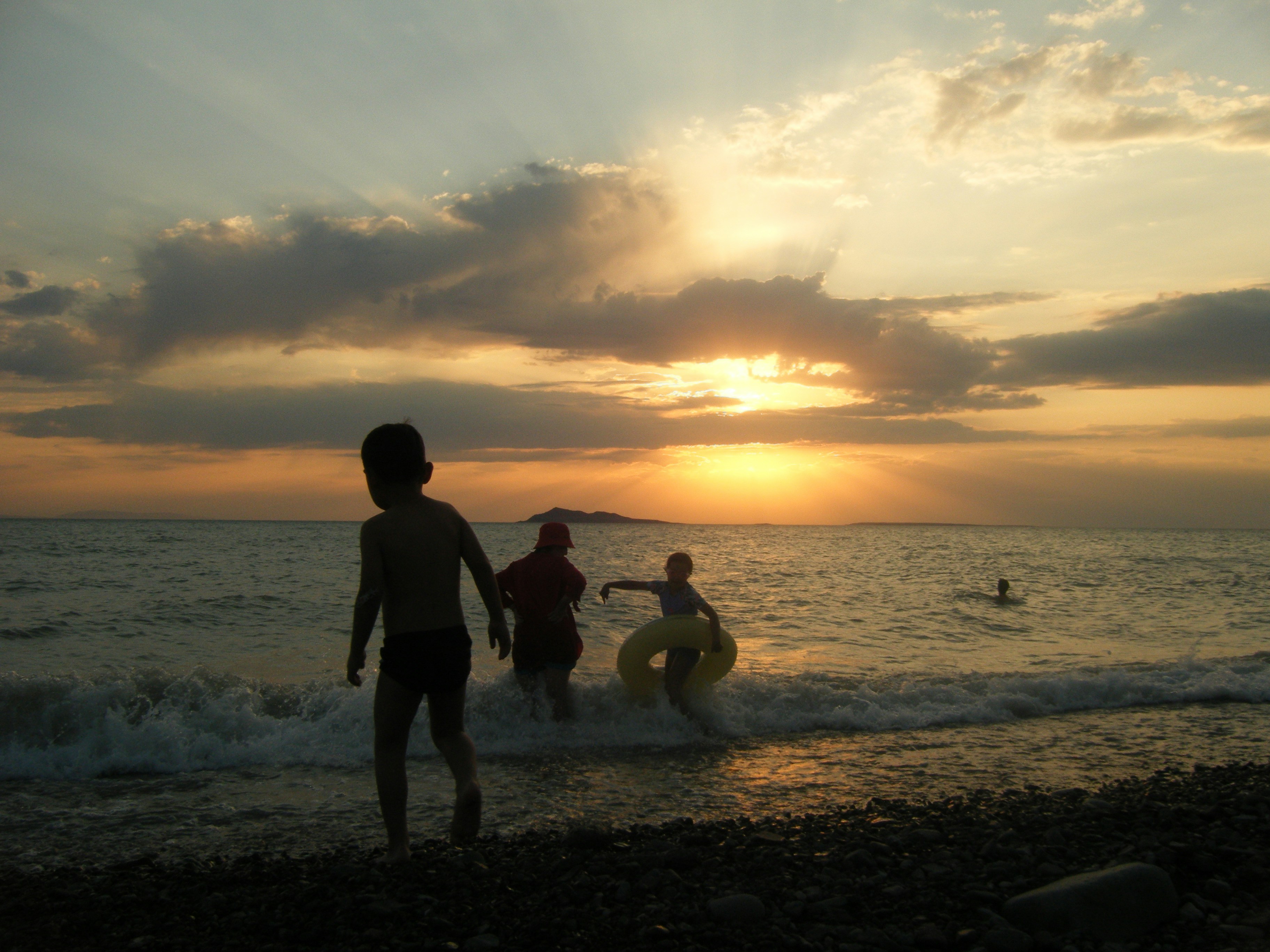 Children playing in the ocean at sunset