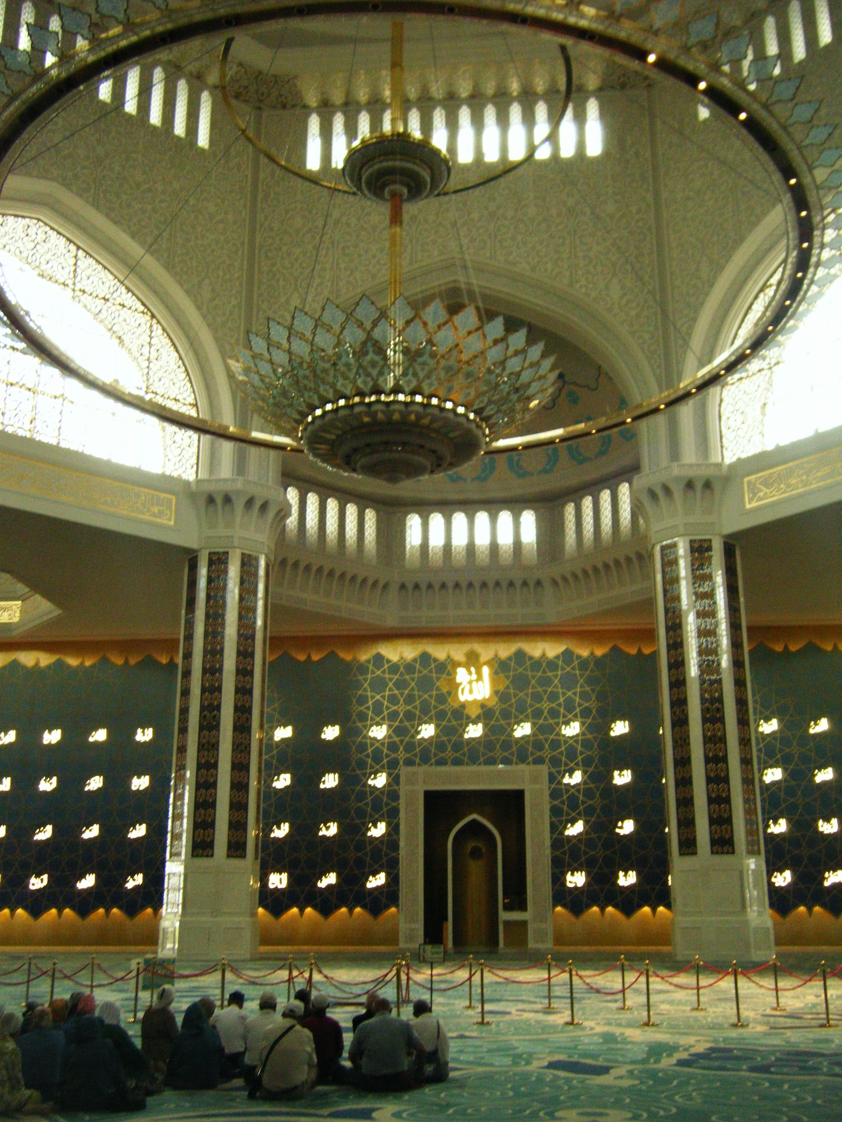 People praying inside a grand mosque with ornate decorations