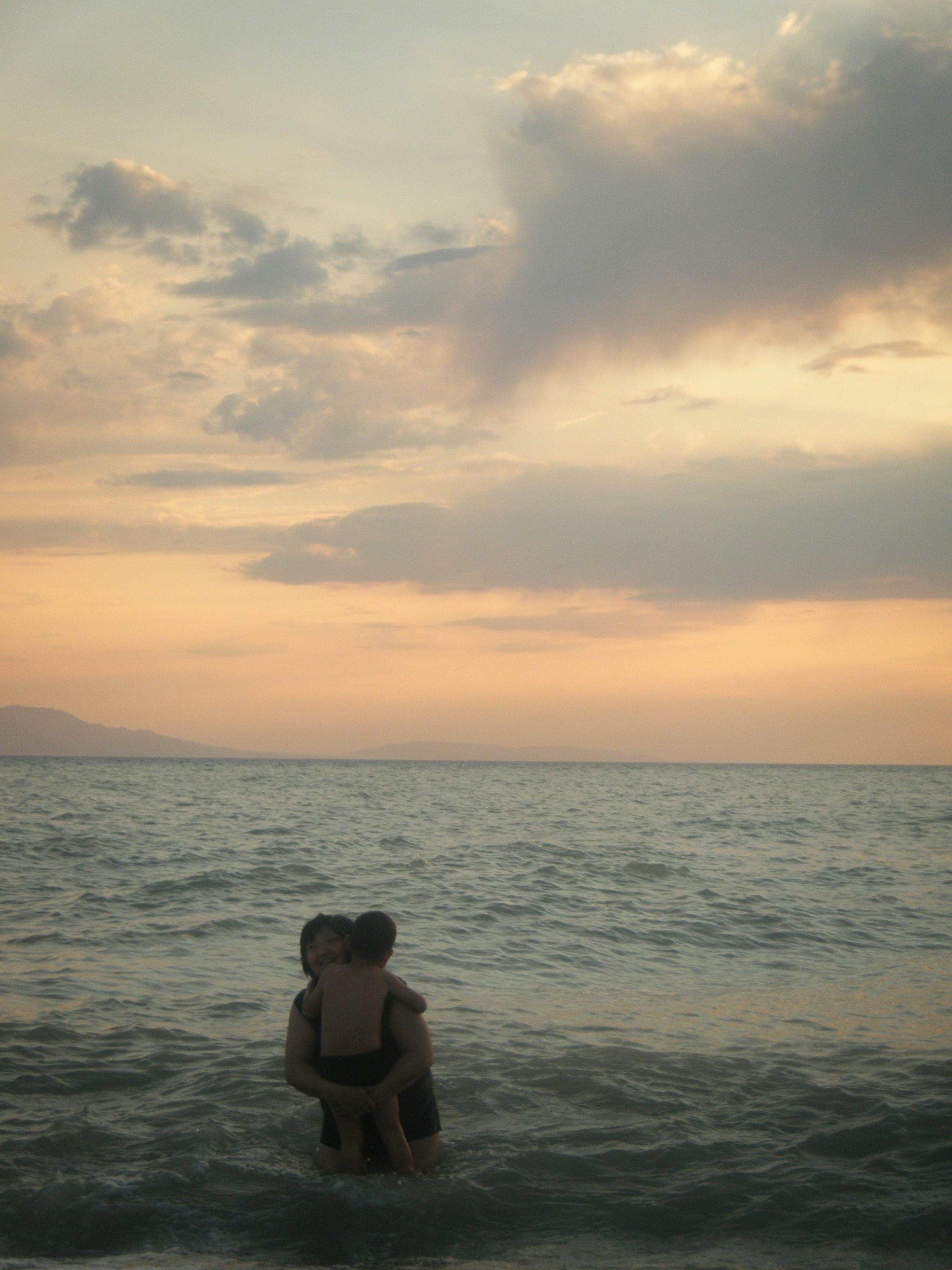 Couple embracing in the ocean at sunset