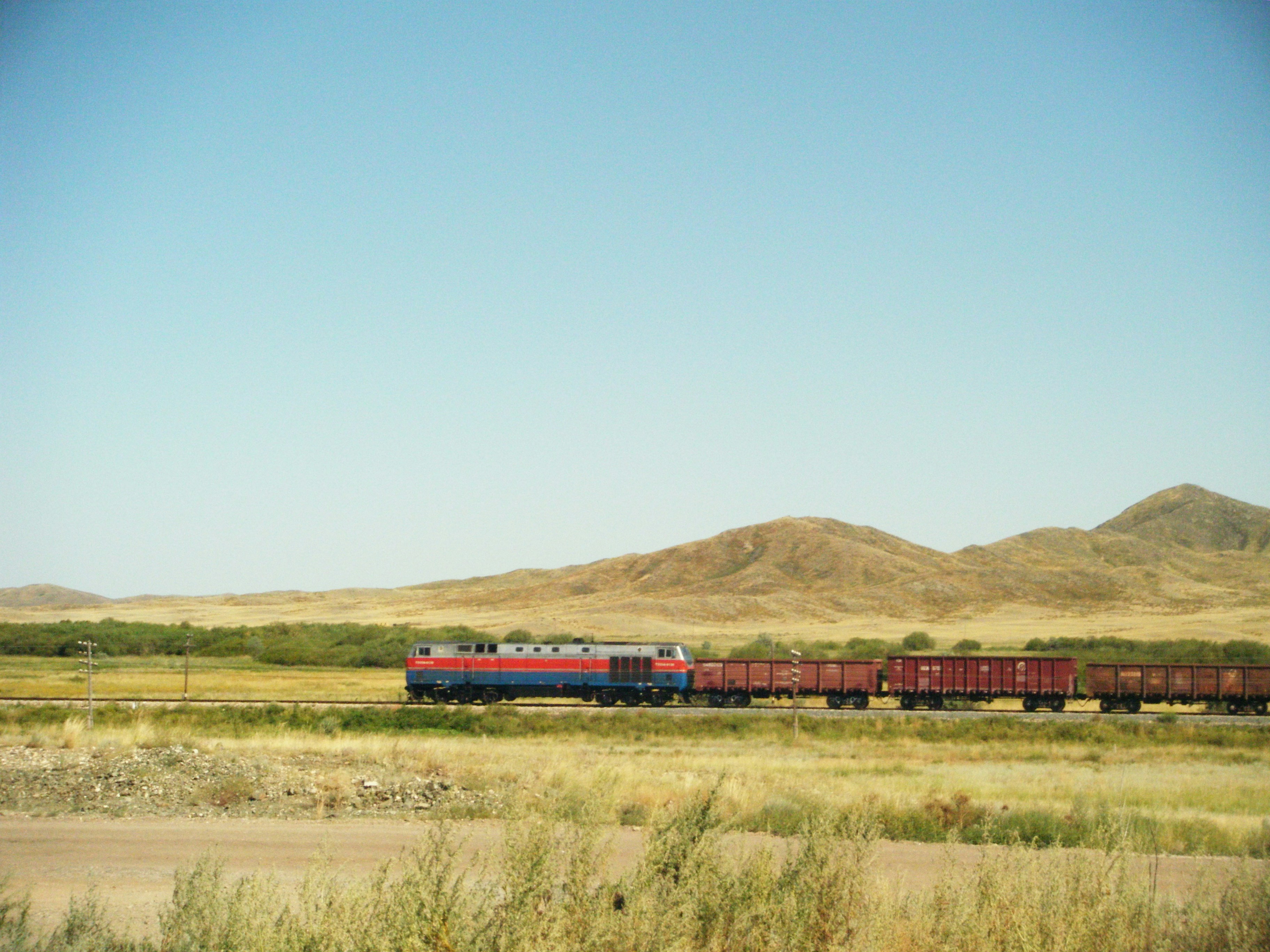 A train travels through a dry, grassy landscape.