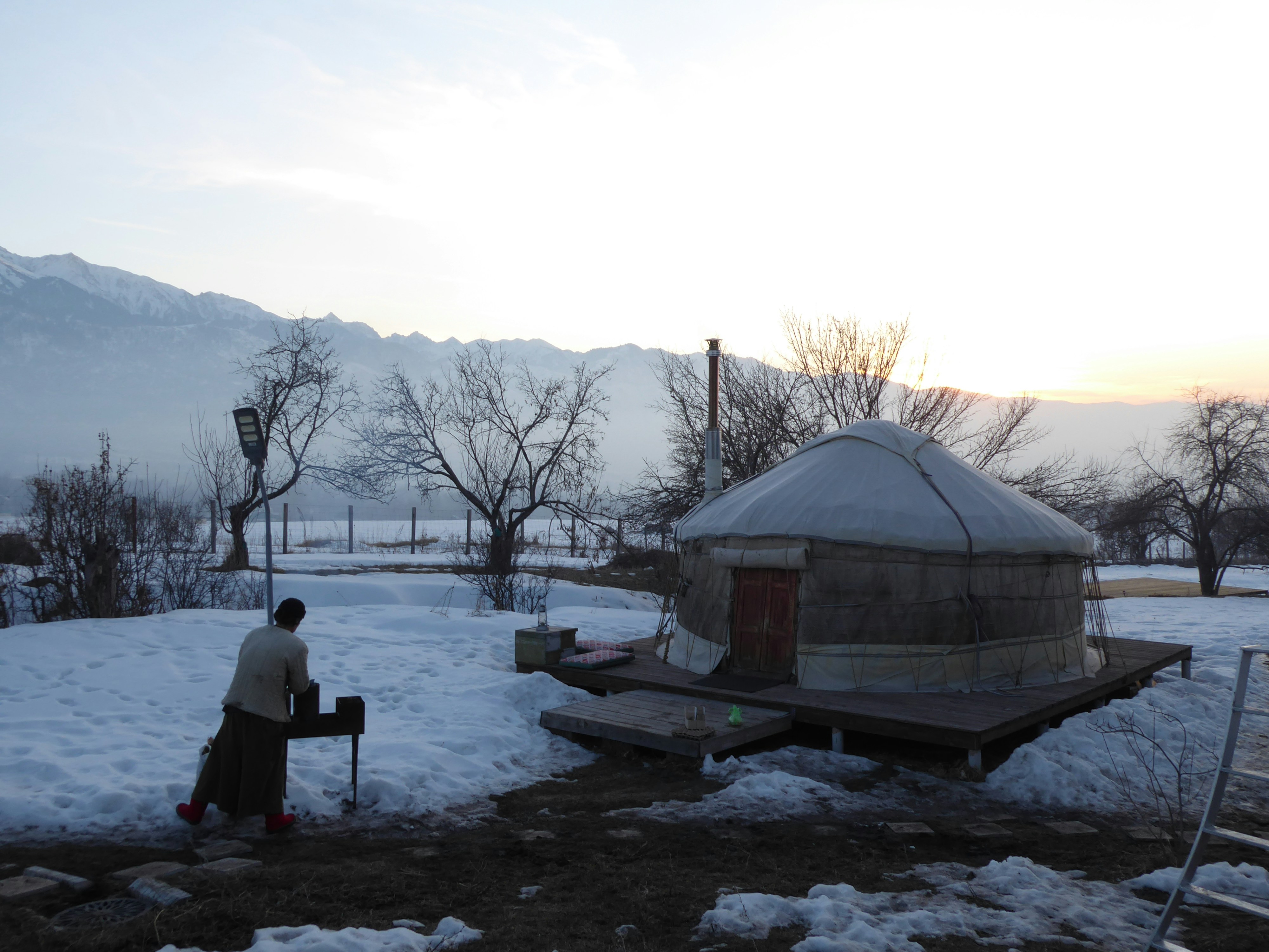 A person works outside a yurt in a snowy landscape.