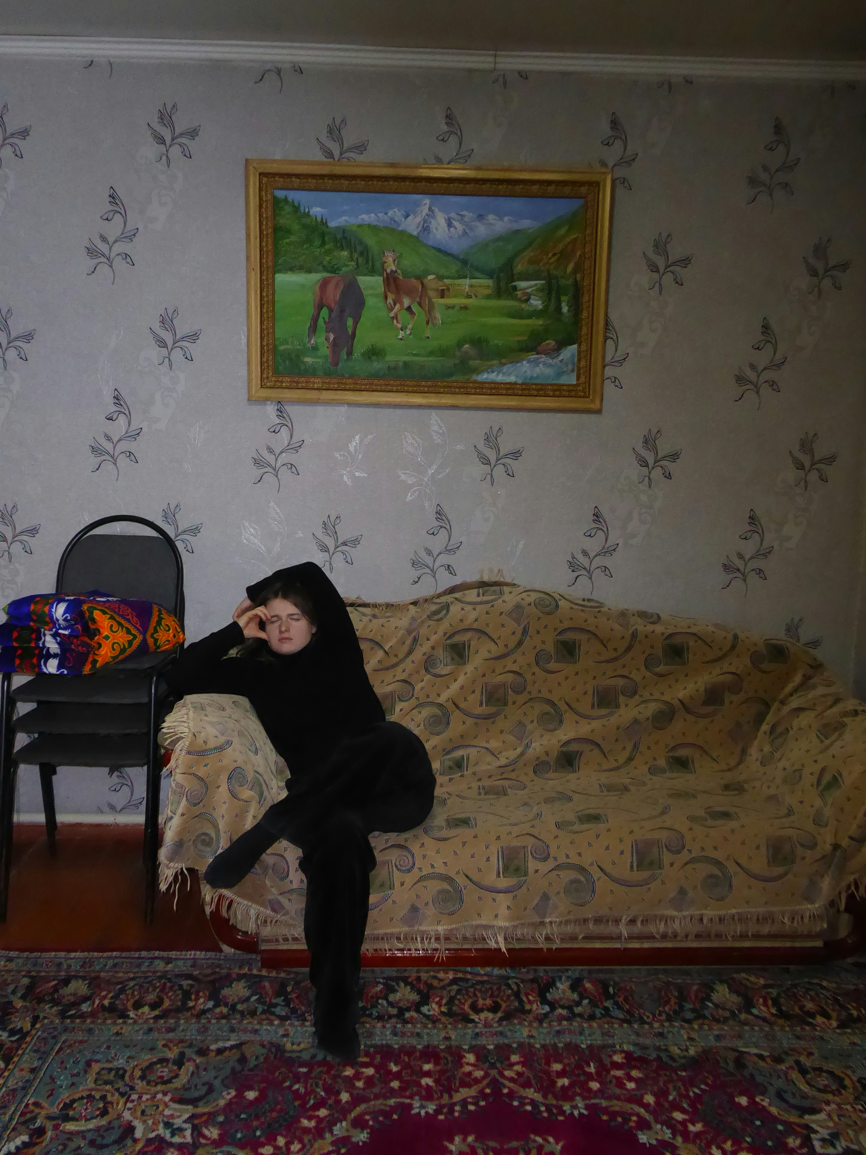 Woman in black sits on a patterned couch