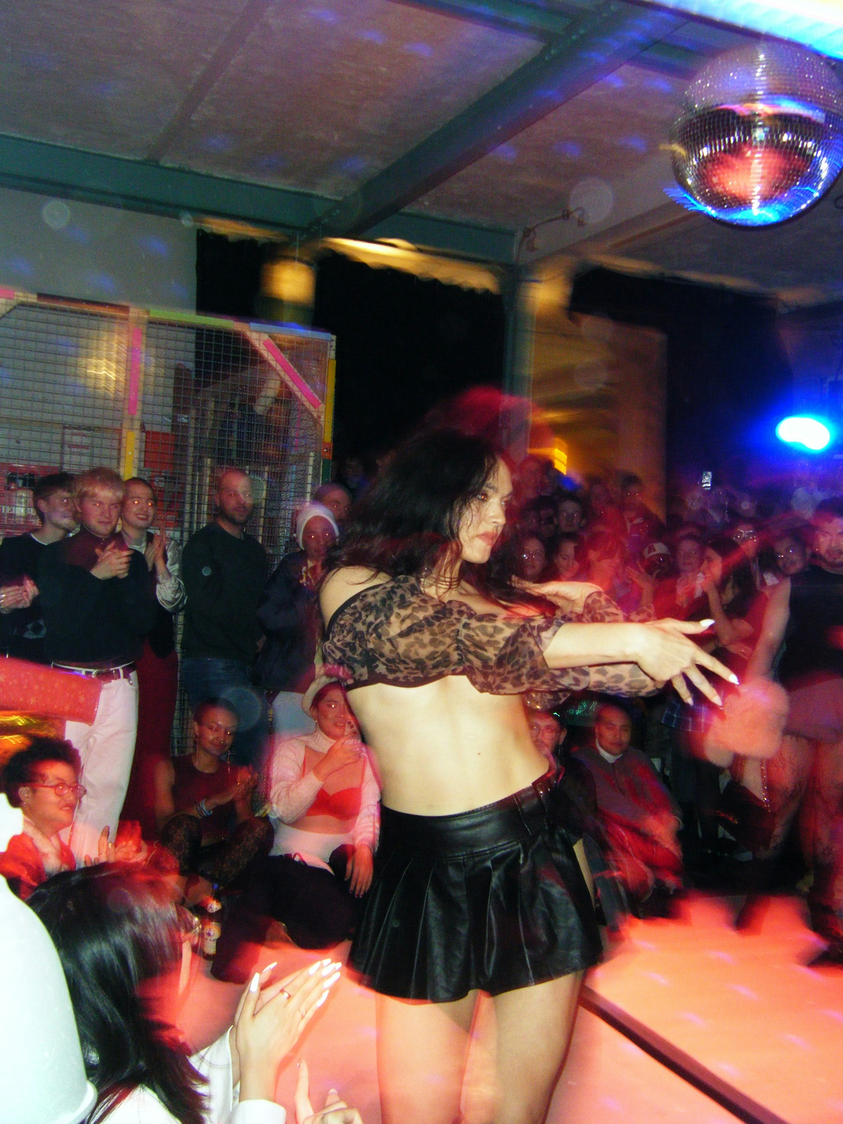 Woman dancing on stage in a nightclub with disco ball.