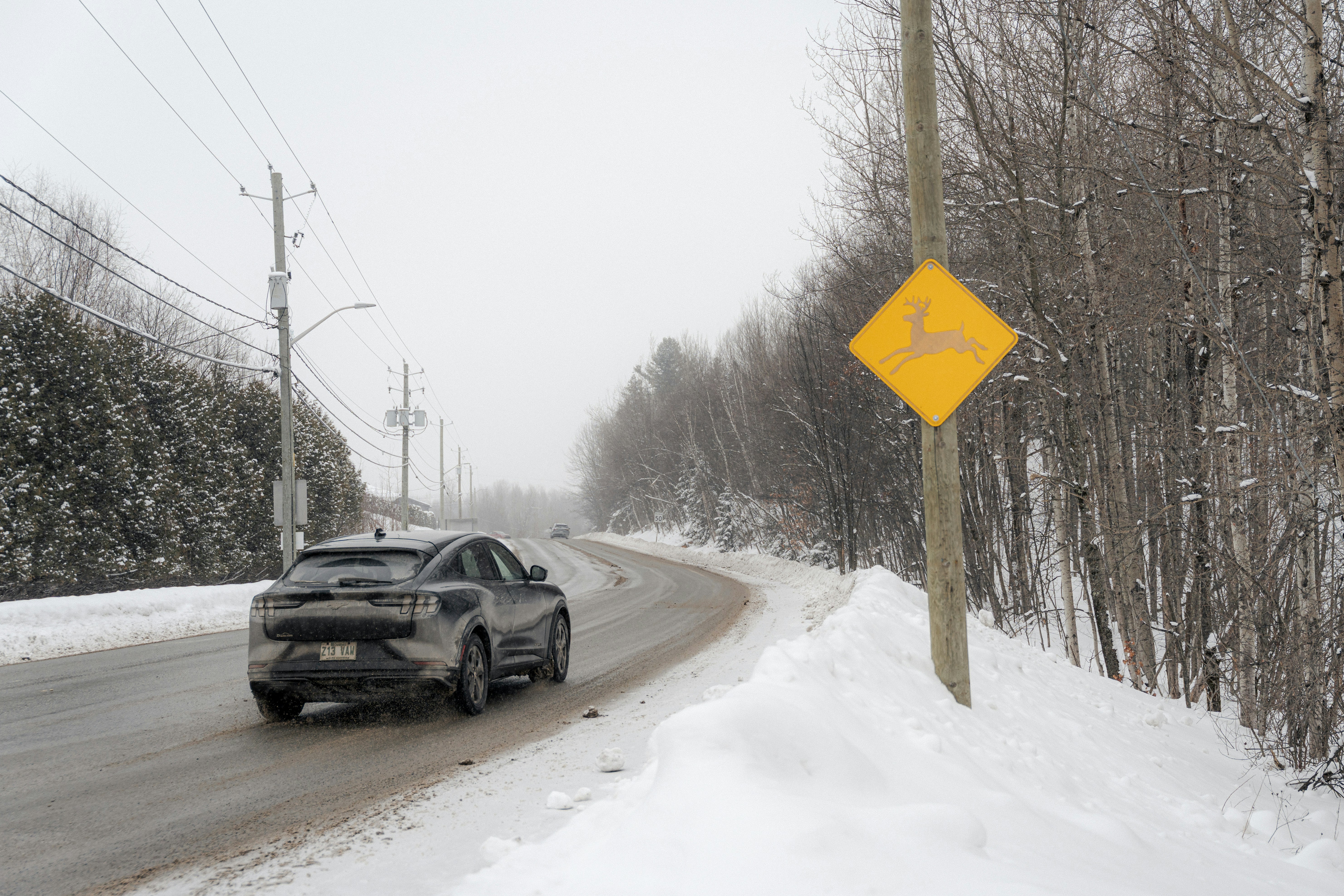 Snowy Roadside Caution: Car Travels a Quiet Winter Bend