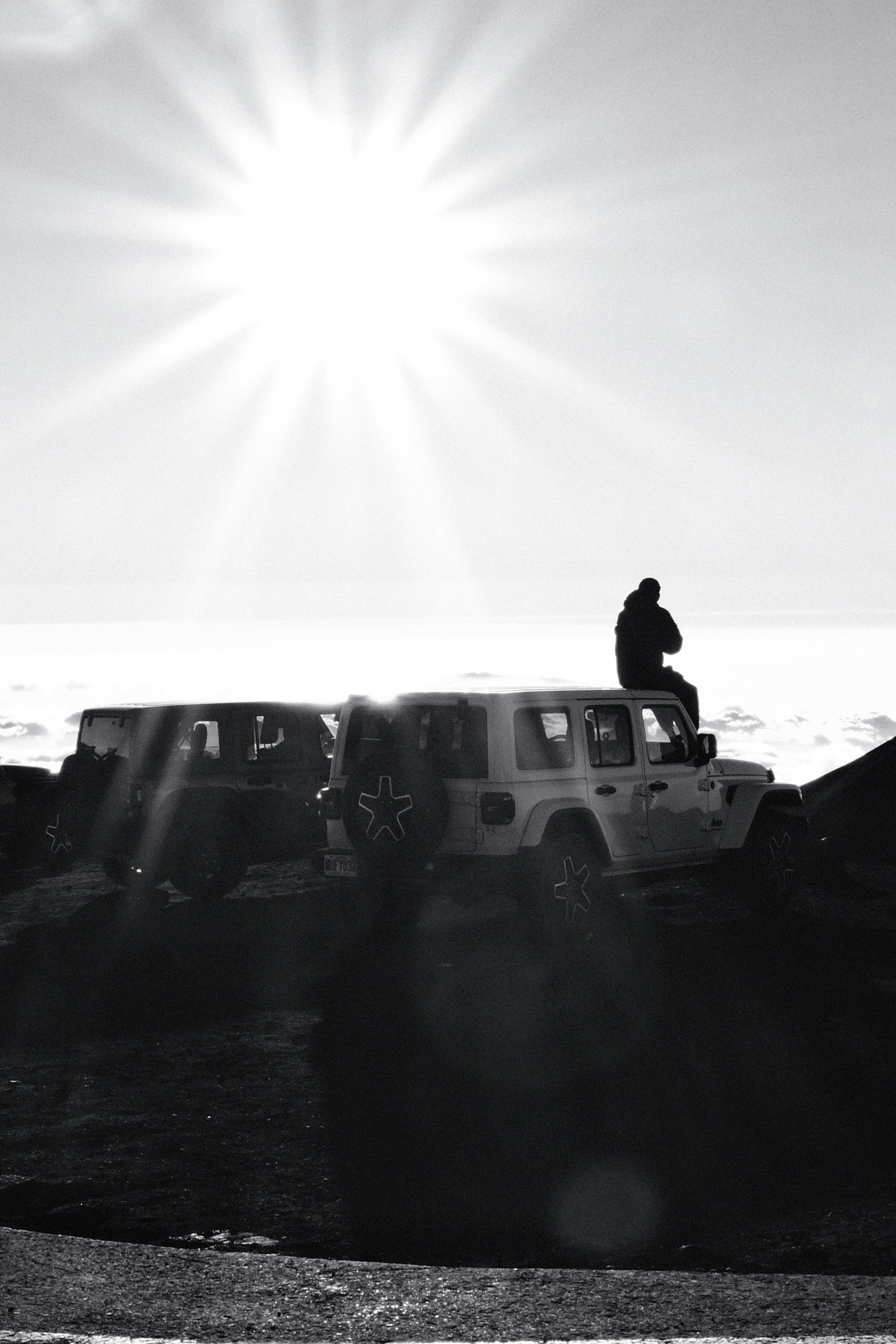 Silhouette on the Rim: A Lone Figure atop a Jeep under Polar Sunlight