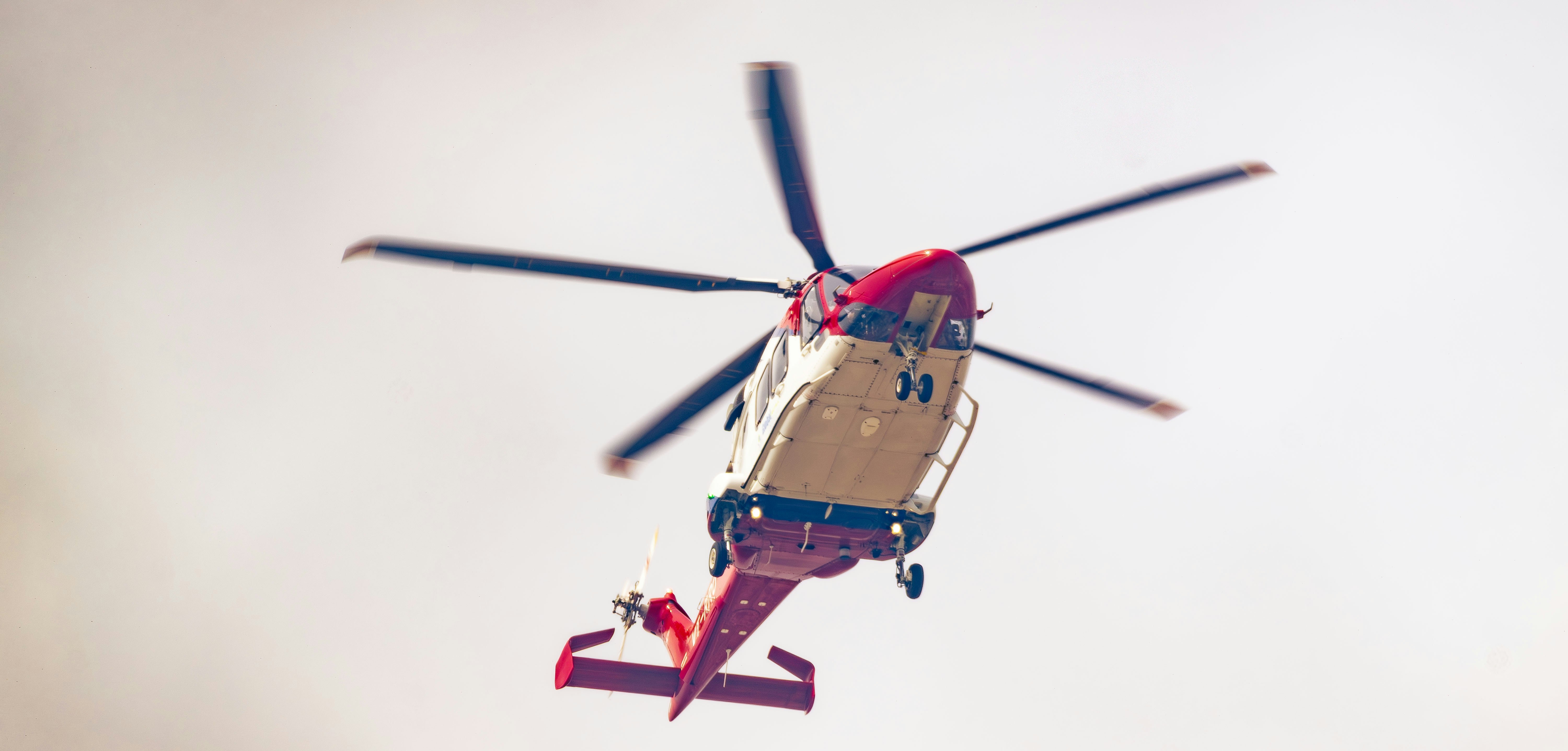 Red-and-cream Rescue Helicopter Climbing Through a Bright Sky