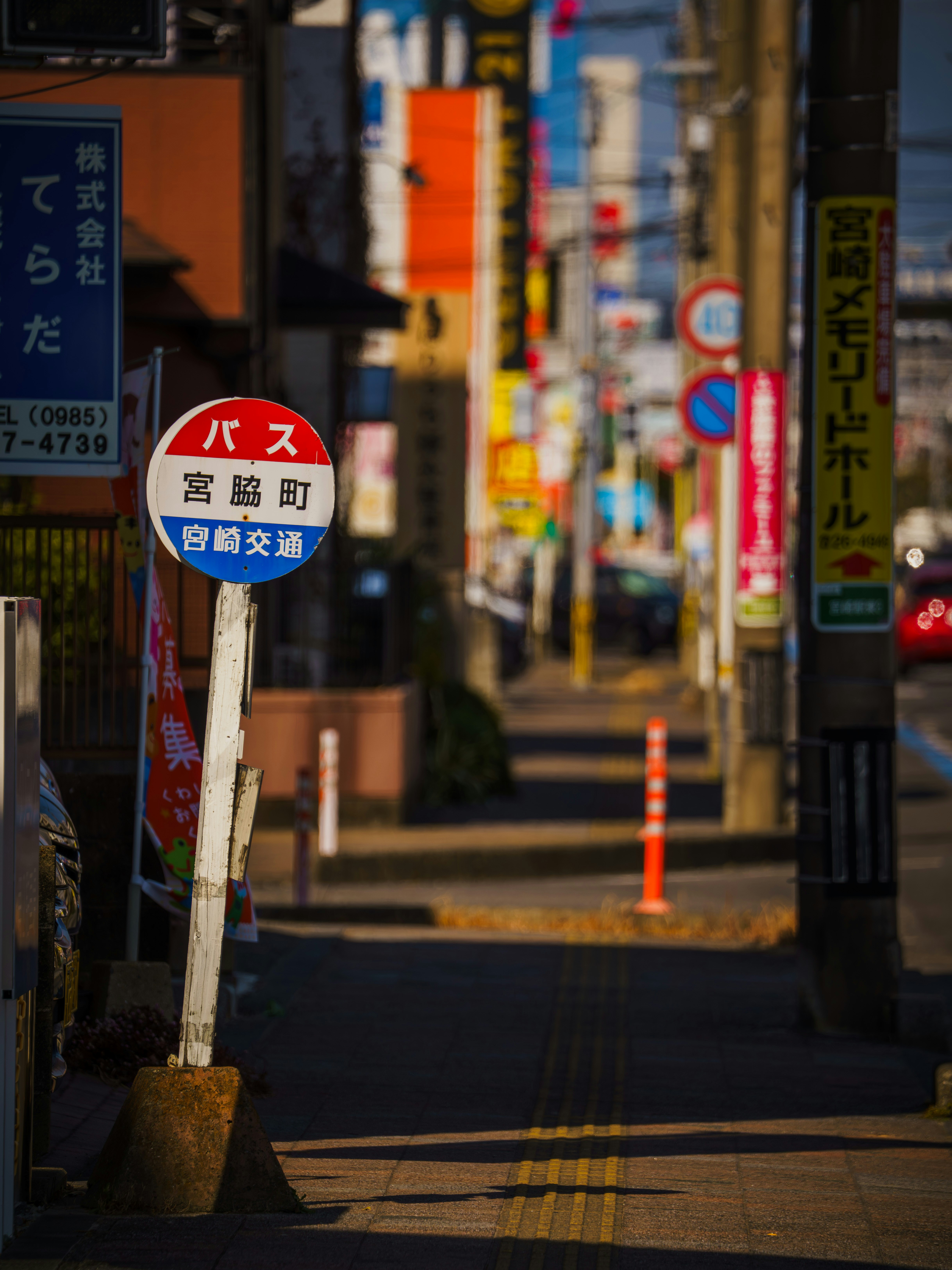 Red and Blue Bus Stop Sign Framing a Neon Street Corridor