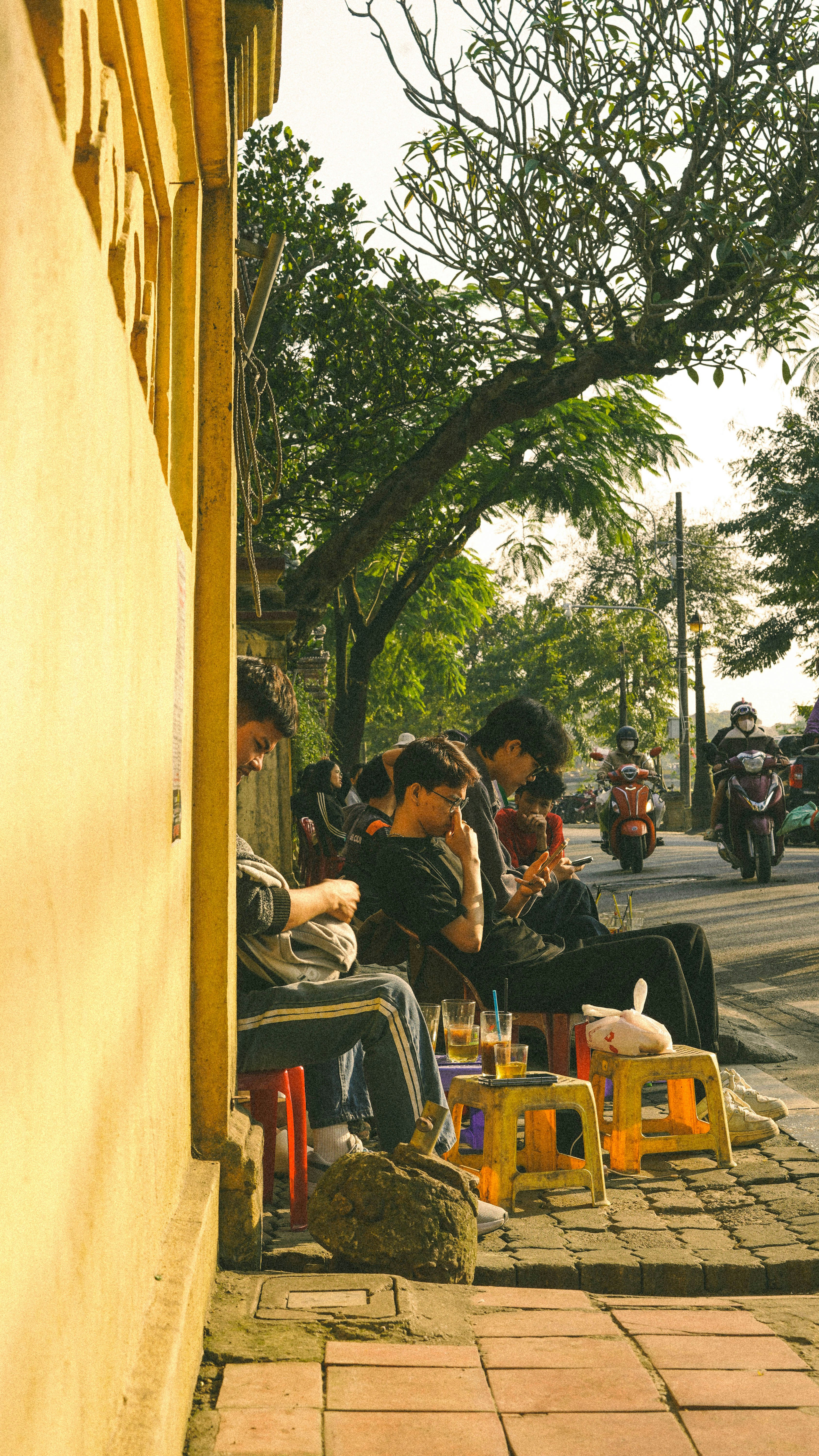 Sunlit Street Chorus: Friends, Phones, and Motorbikes