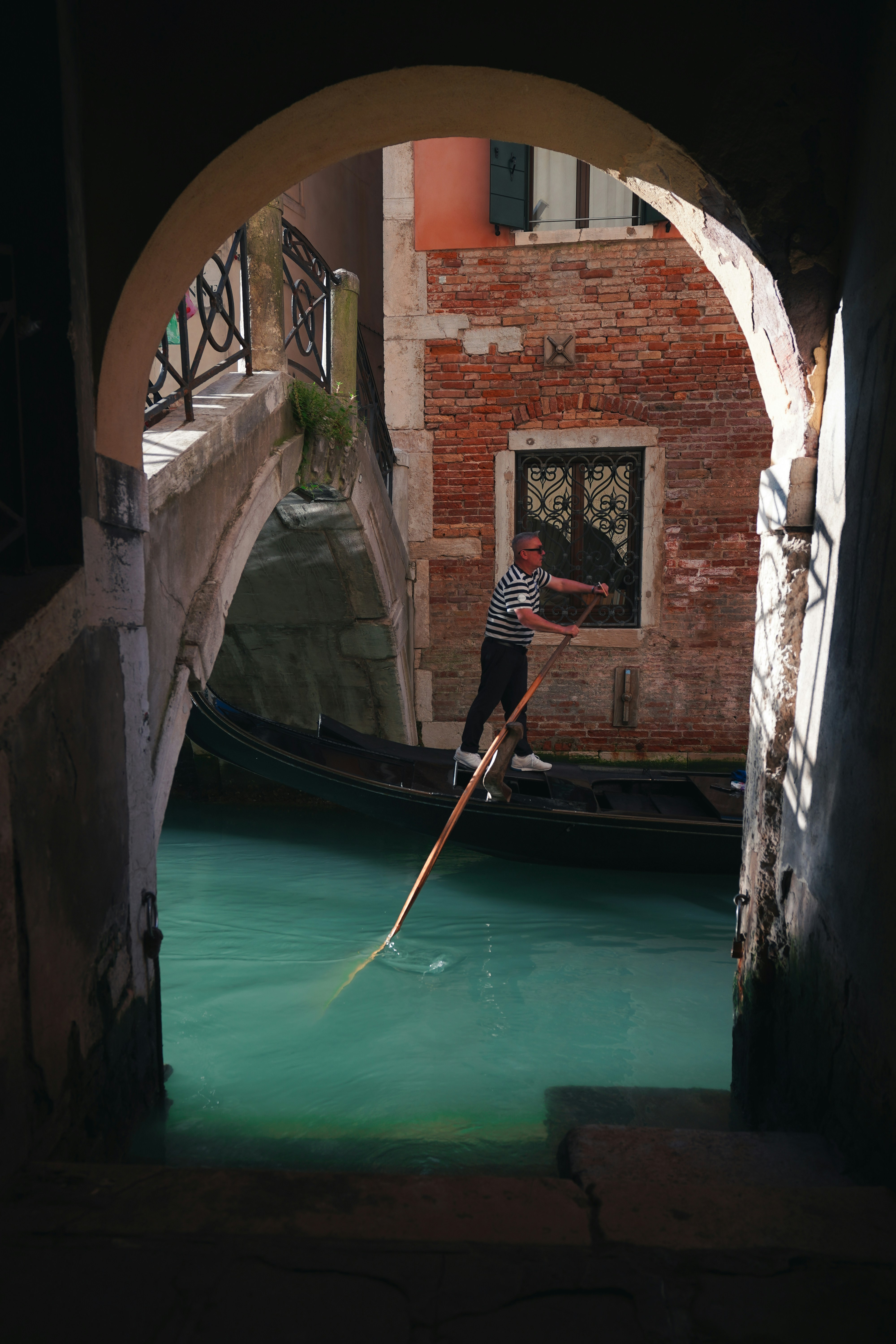 Gondola Pulse: A Gondolier Navigates the Narrow Canal Beneath a Stone Arch