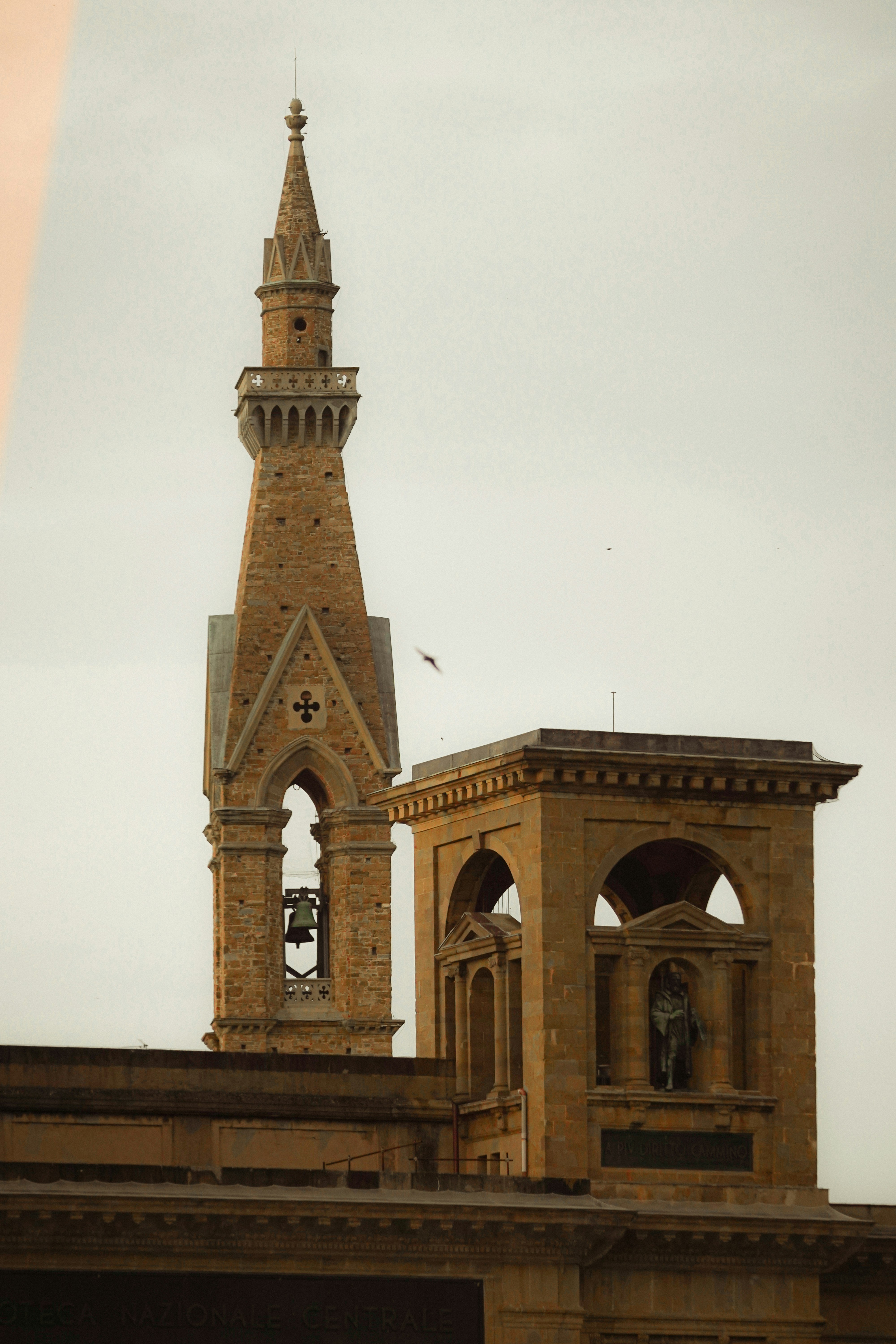 Bell Tower and architectural arcade rising over a sunlit rooftop